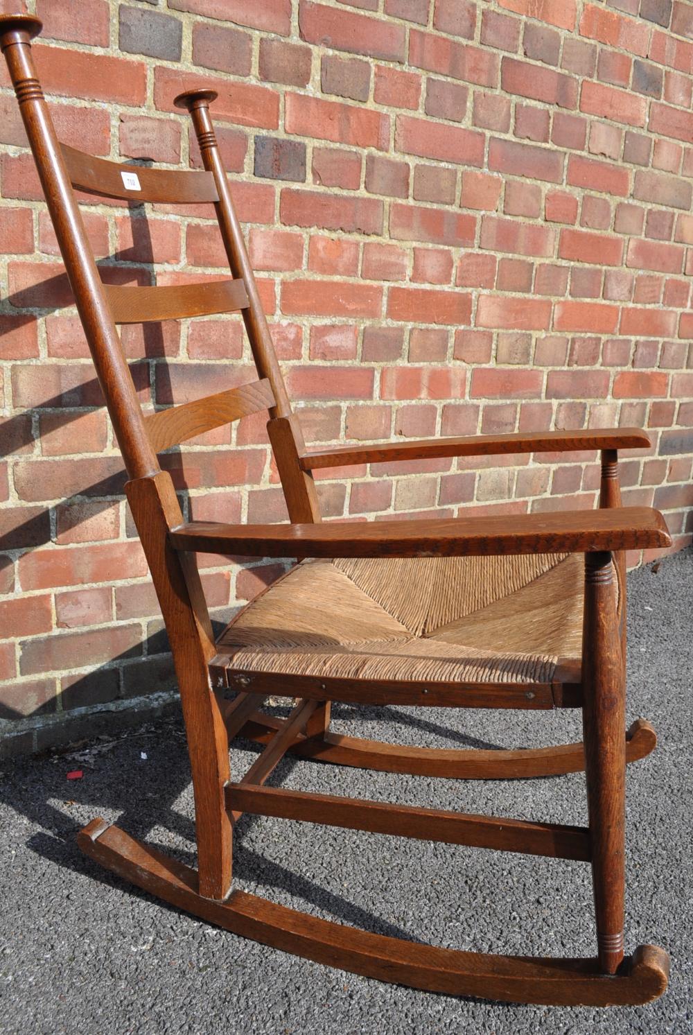 A Walter Cave design rocking chair, of stylised form with rush seat ...