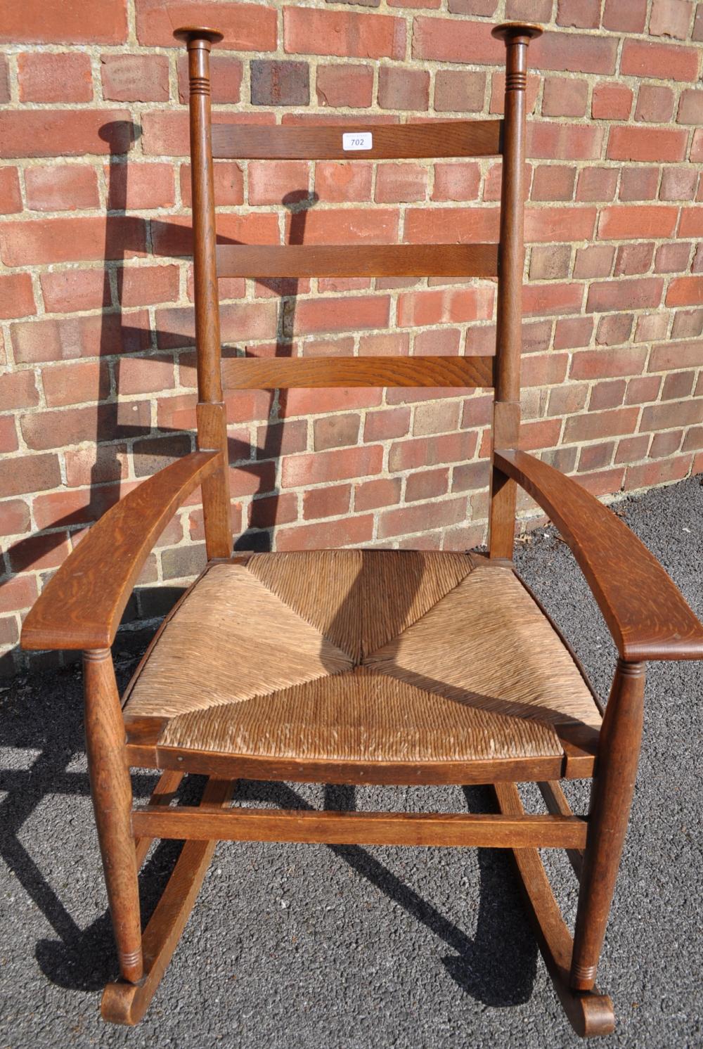 A Walter Cave design rocking chair, of stylised form with rush seat ...
