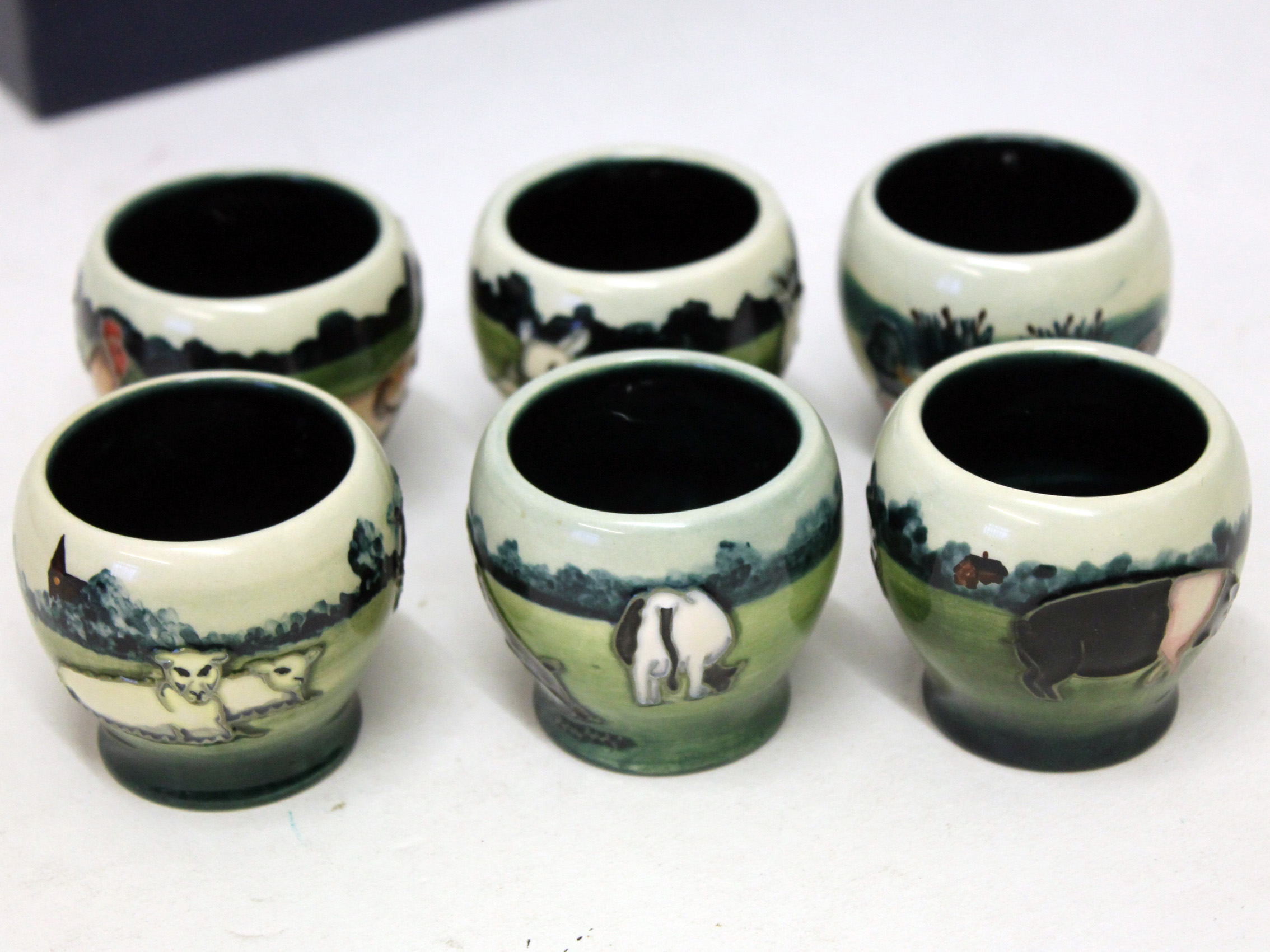 A set of six Moorcroft pottery egg cups each decorated with farm yard ...