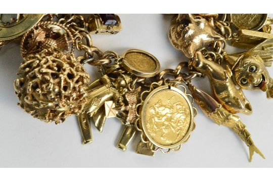 An exceptionally large 9ct gold charm bracelet set with numerous ...