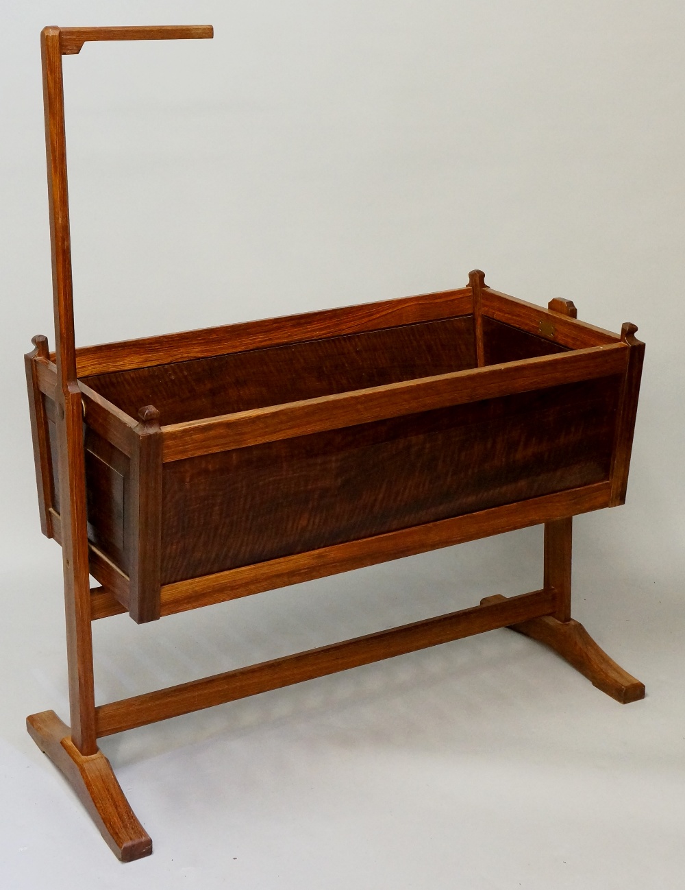 An Arts & Crafts hardwood cradle the rectangular panelled figured ...