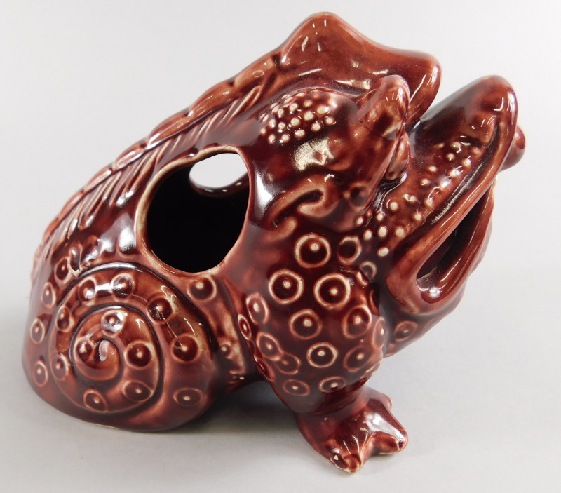 A Burmantofts type grotesque model of a seated frog, with a red glaze ...