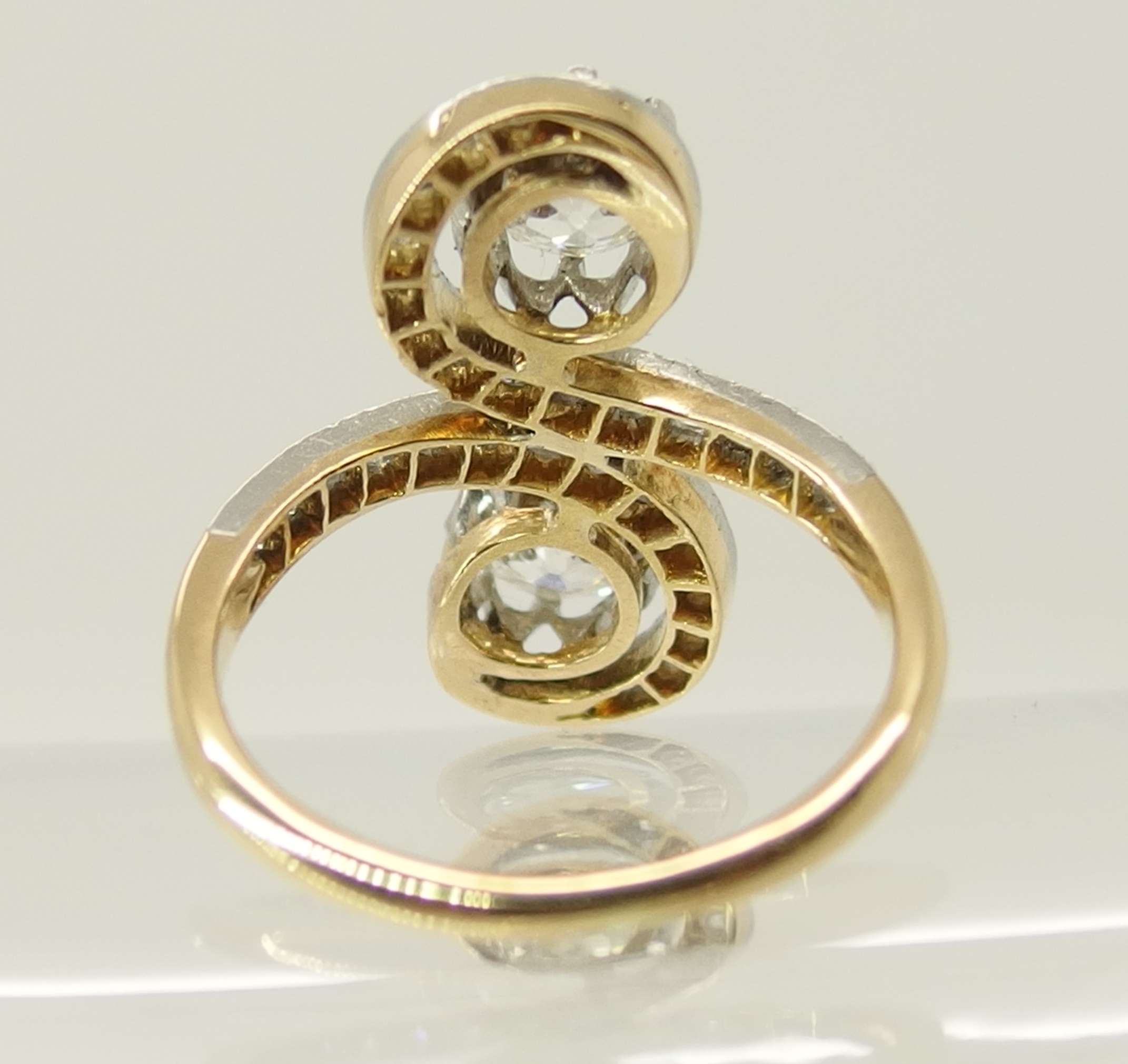 A TWIN DIAMOND SCROLL SHAPED RING set in yellow and white metal, the ...