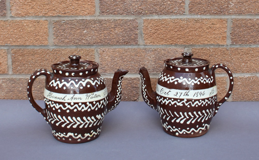 A pair of Wetheriggs pottery teapots and covers, decorated in white ...