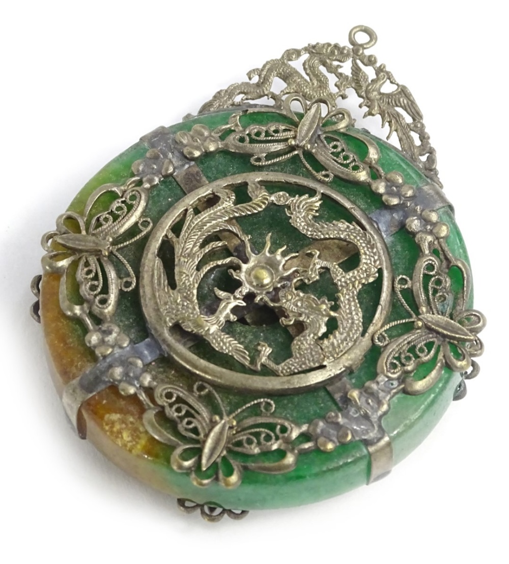A Chinese silver dragon and phoenix pendant, the jade of two colour ...