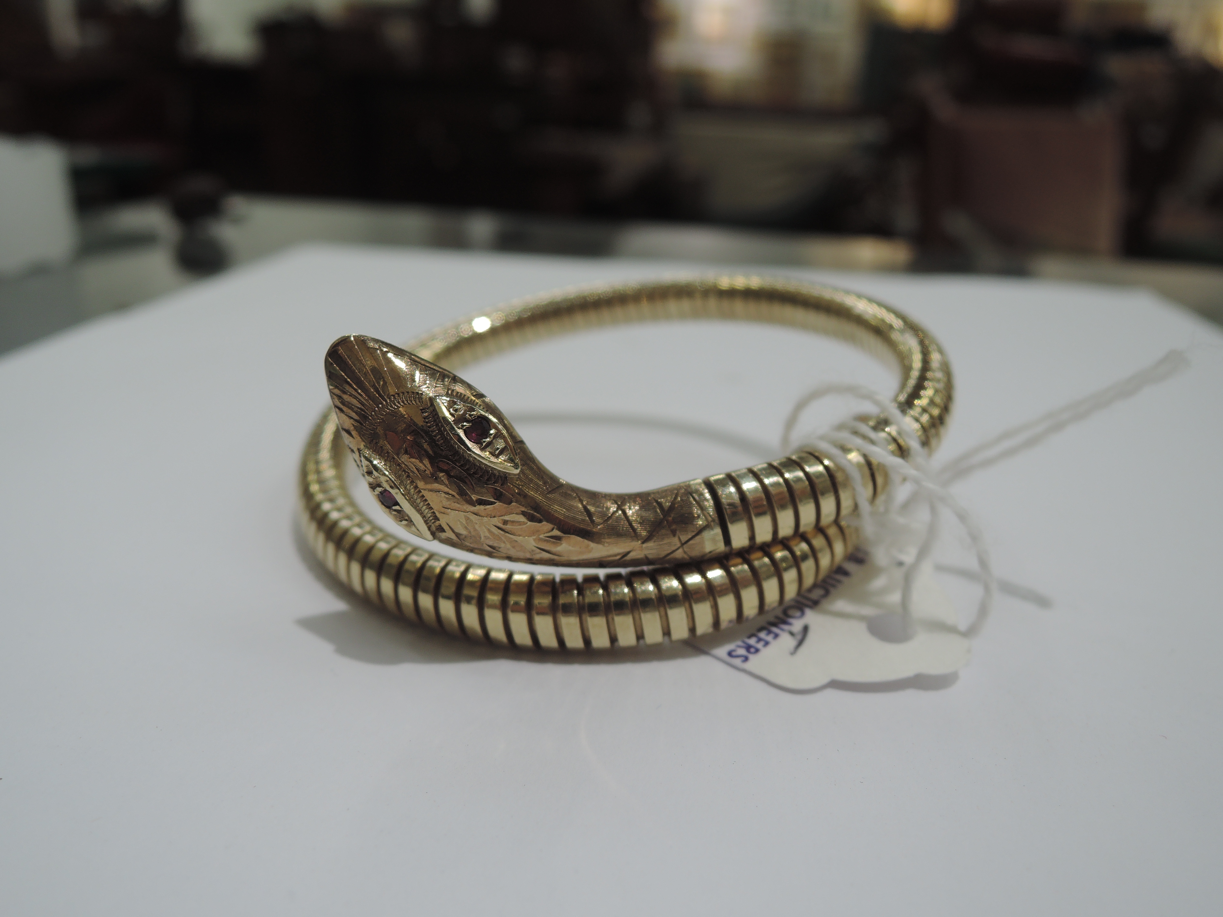 A 9ct gold snake bangle having ruby eyes and engraved decoration to ...