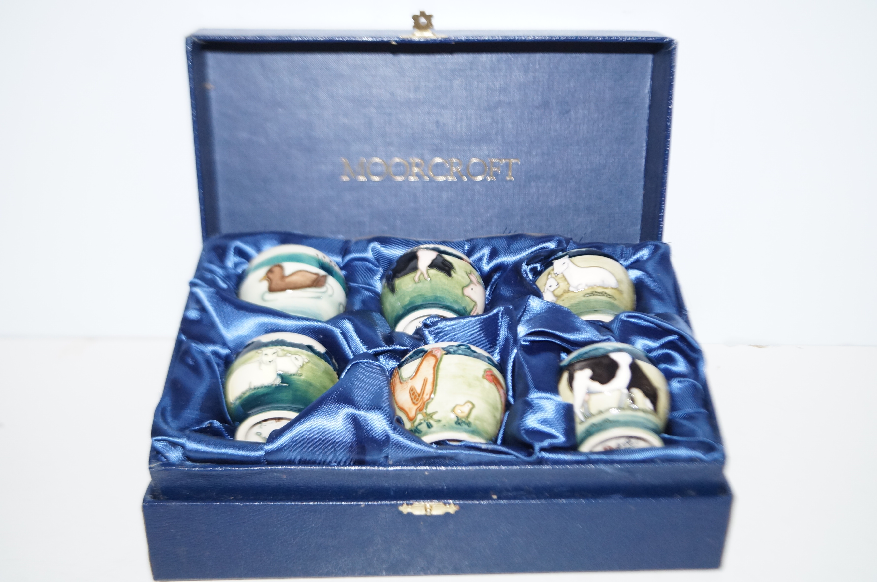 Case set of 6 Moorcroft egg cups, farmyard animal pattern.