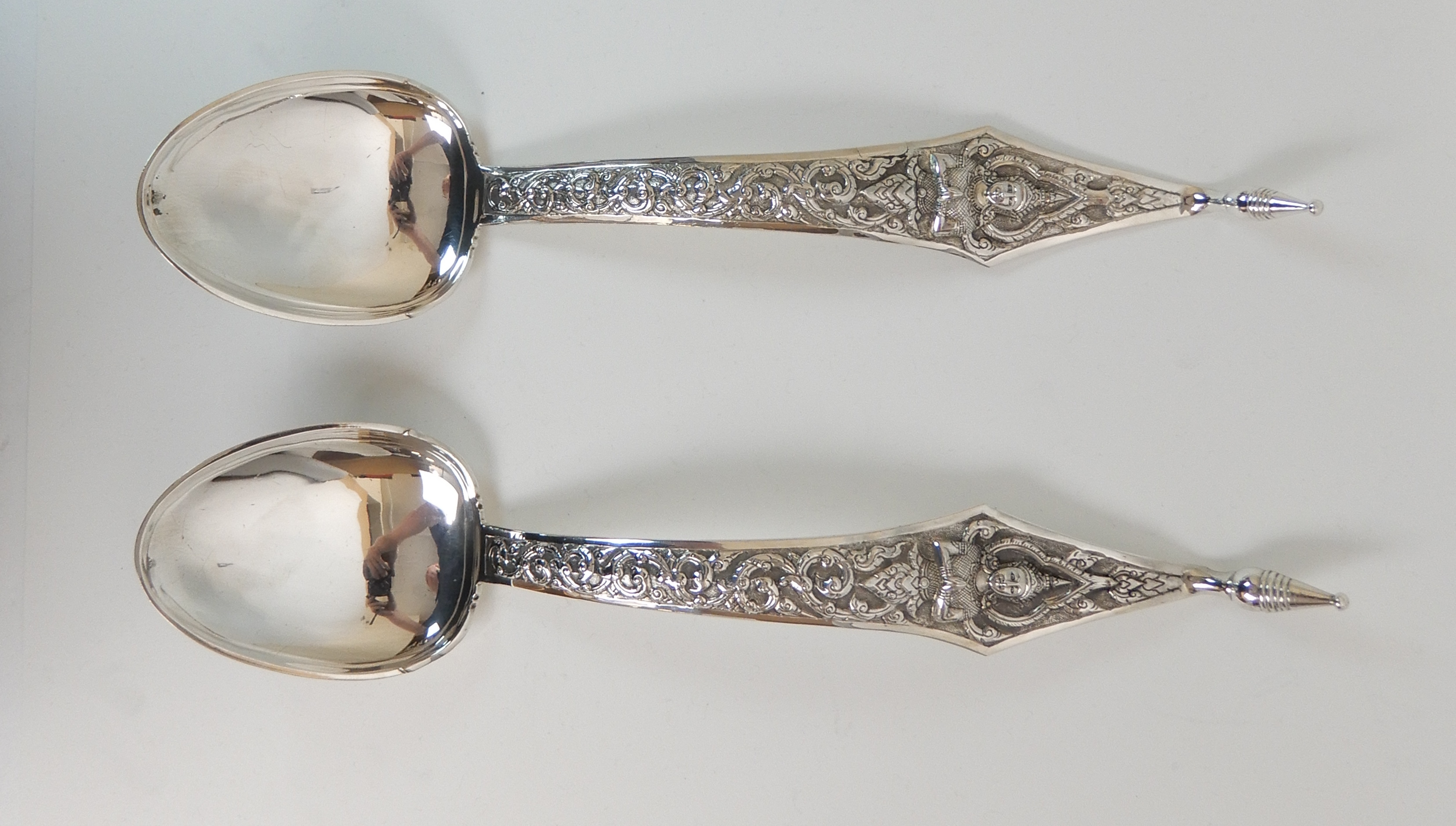 A PAIR OF EASTERN SERVING SPOONS marked Thailand sterling, the shaped ...