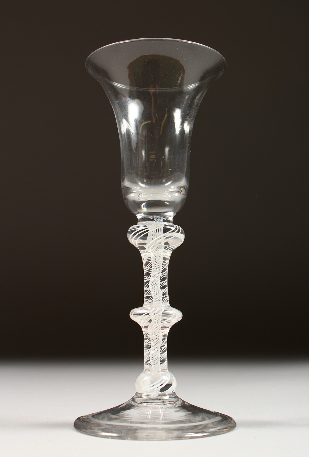 A GEORGIAN WINE GLASS with inverted bell shaped bowl and three knops to ...