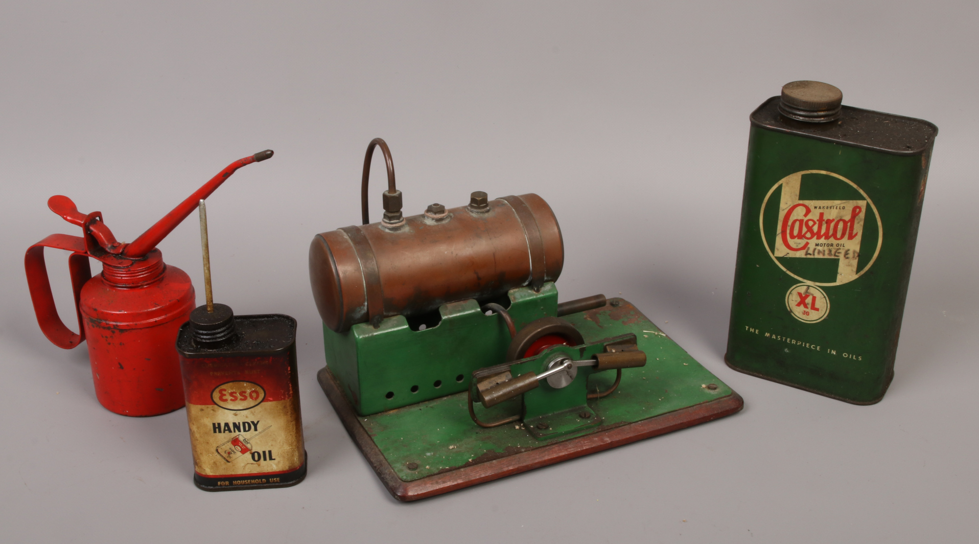 A vintage stationary steam engine along with three oil cans to include ...
