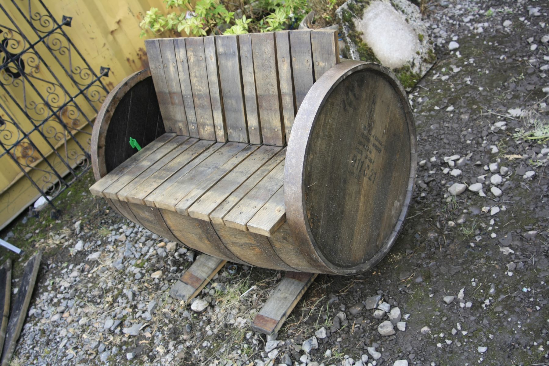 A BOURBON WHISKEY BARREL GARDEN BENCH with barrel staves as seat, back ...