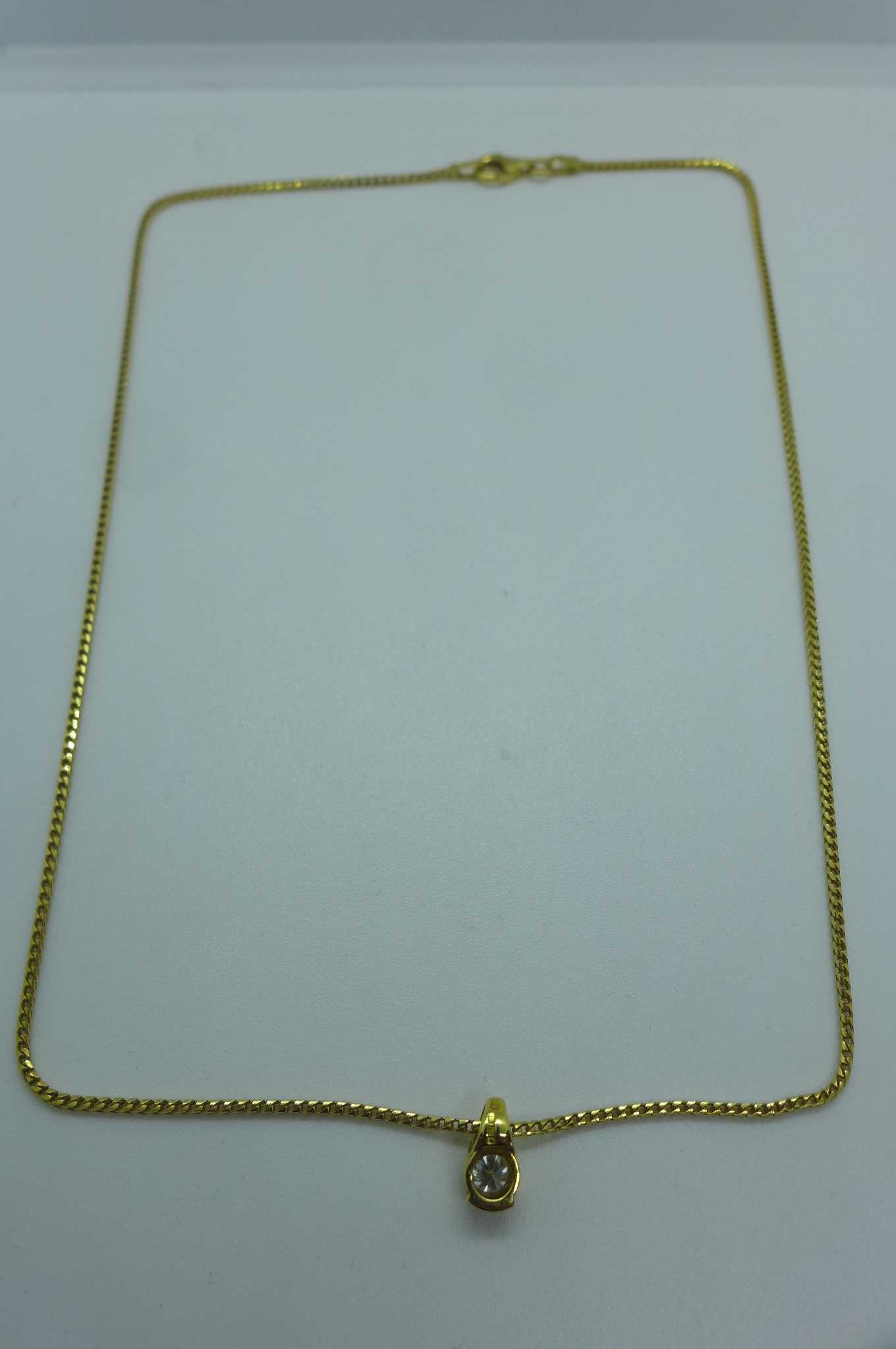 An 18ct gold diamond single stone pendant on an 18ct chain, both ...