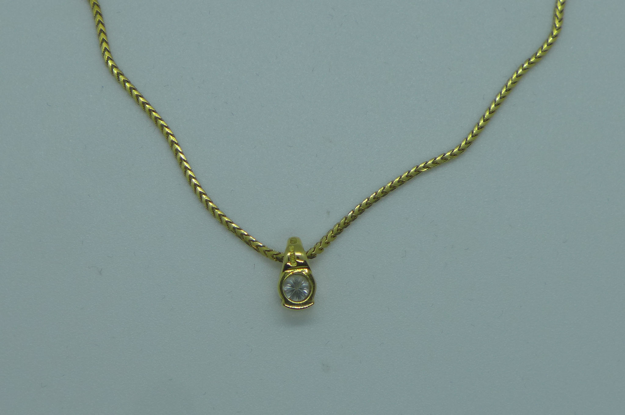 An 18ct gold diamond single stone pendant on an 18ct chain, both ...