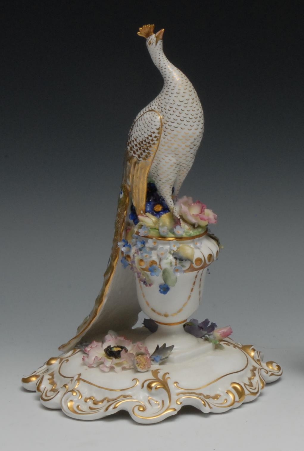 A Royal Crown Derby Peacock, standing on a flower encrusted urn, tail ...