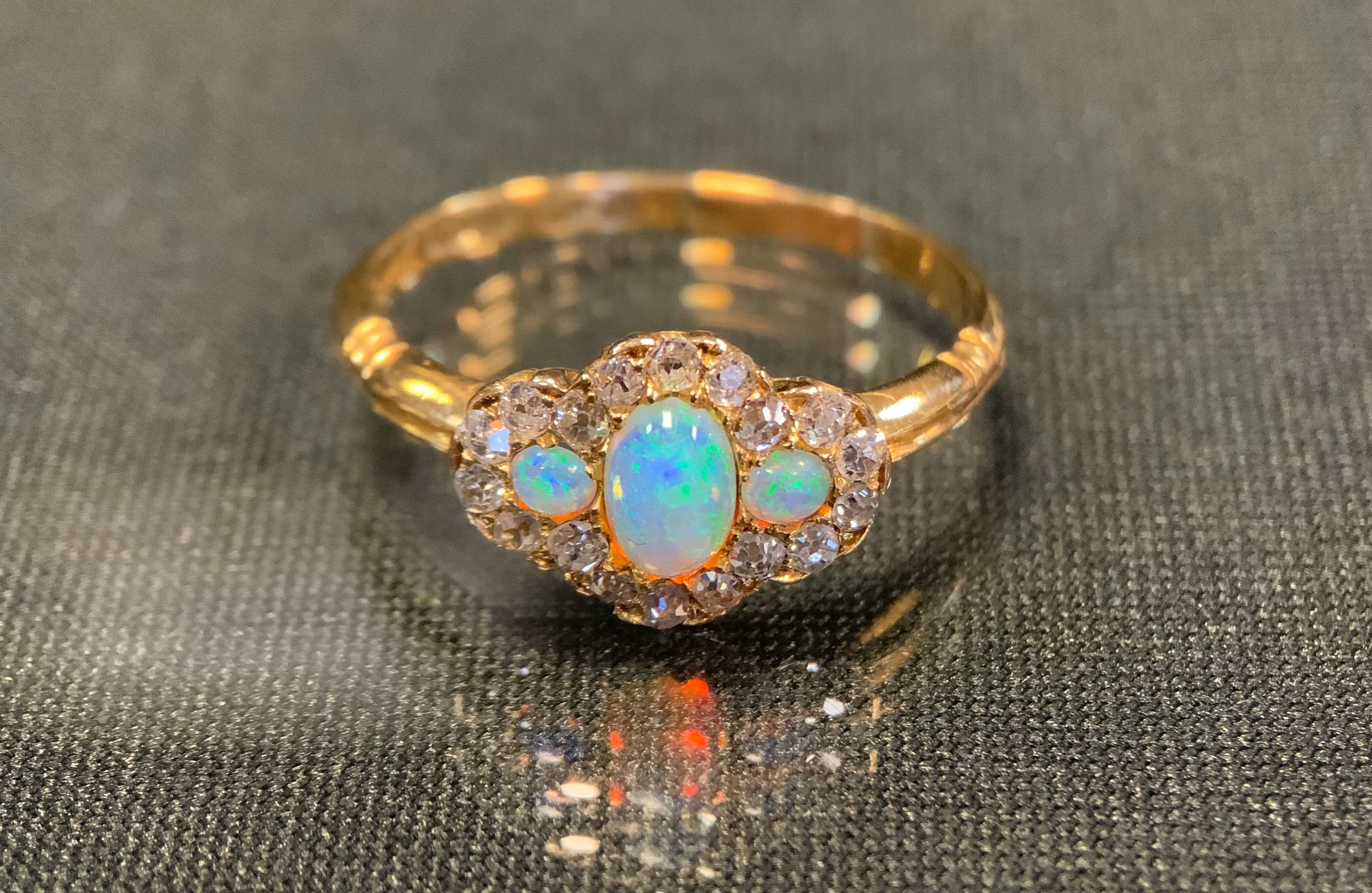 A diamond and opal cluster ring, with three oval opals flashing green ...