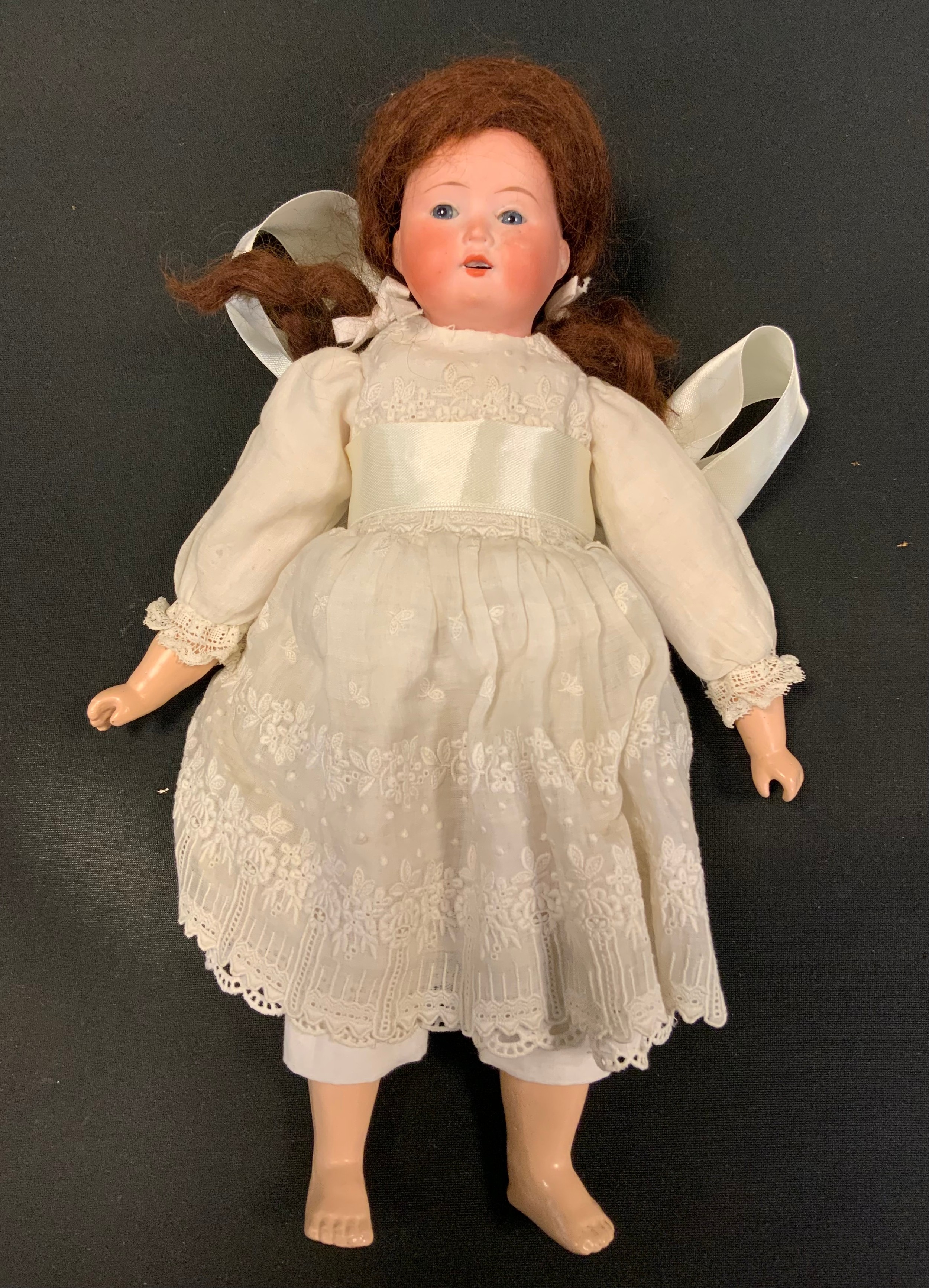 A German porcelain headed shoulder doll, fixed blue eyes, open mouth ...