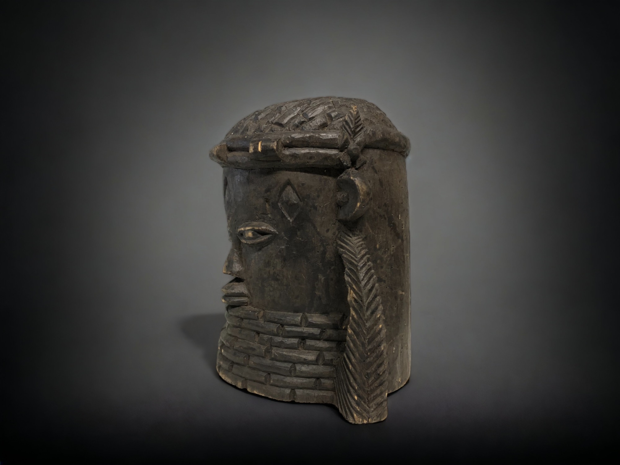 A CARVED BENIN WOODEN HEAD OF AN OBA. IN CHARACTERISTIC STYLE, WITH ...