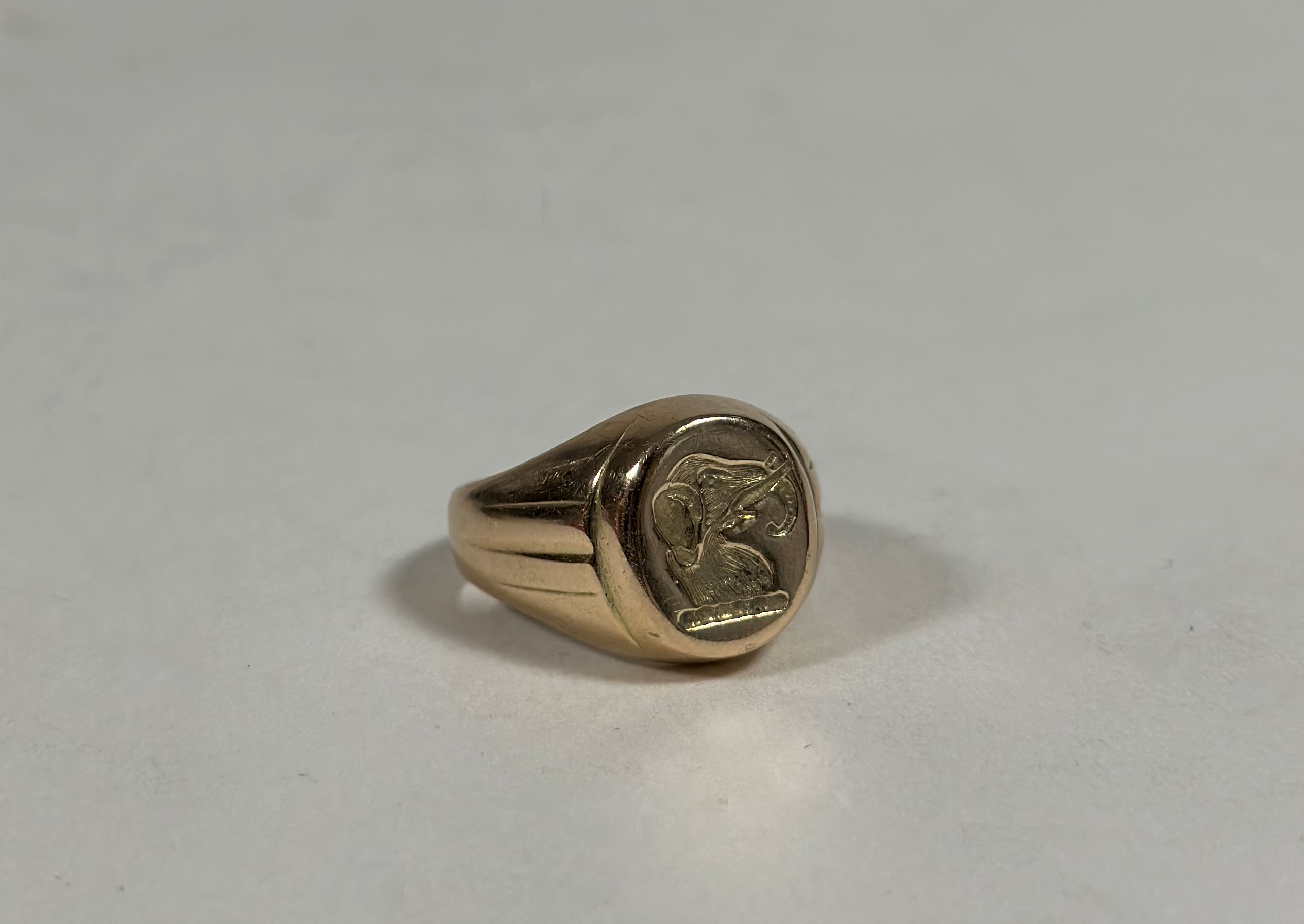 A 14ct gold signet ring, the oval plaque engraved with a crest on a ...
