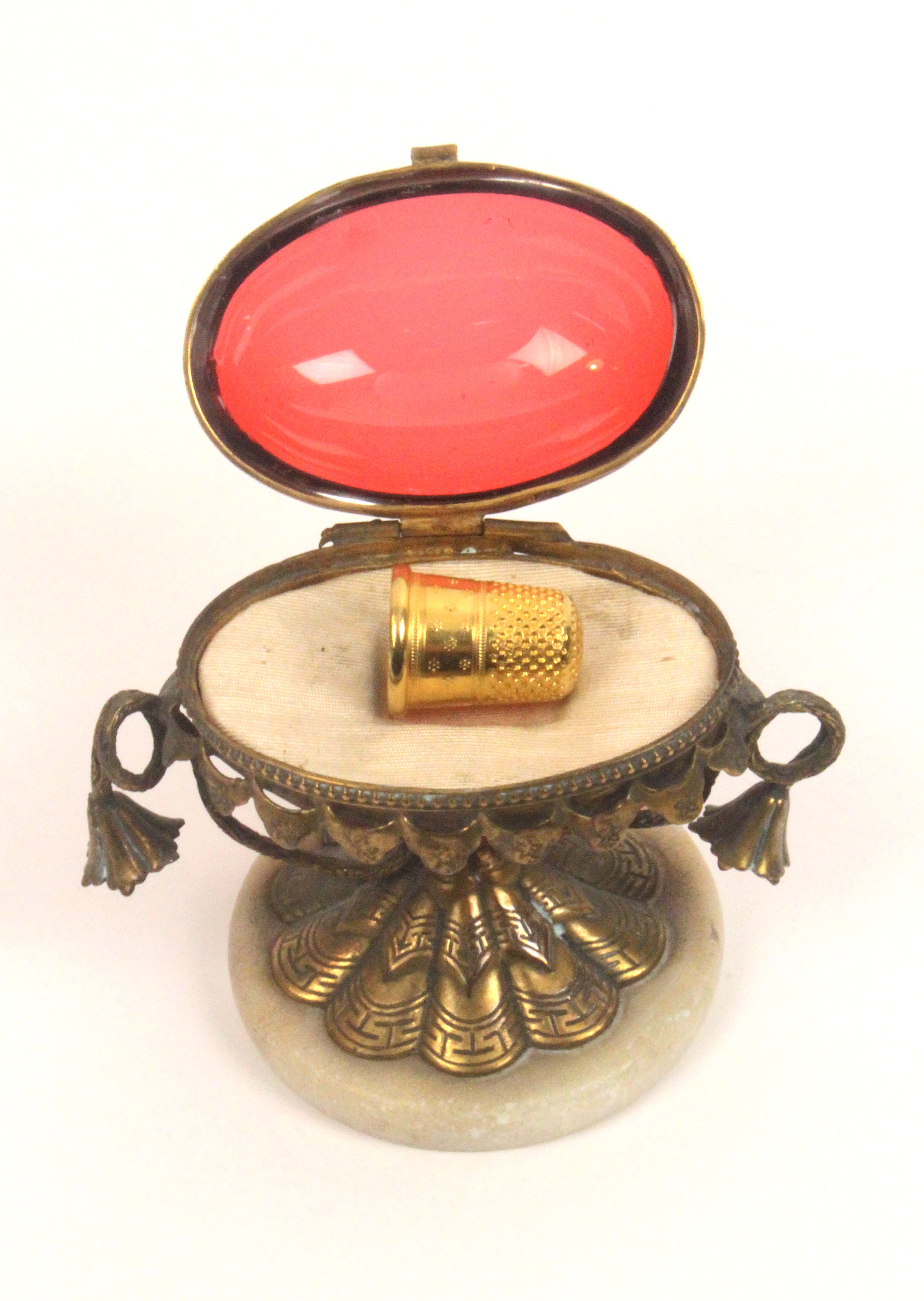 An elaborate French thimble case, the circular alabaster base to a gilt ...