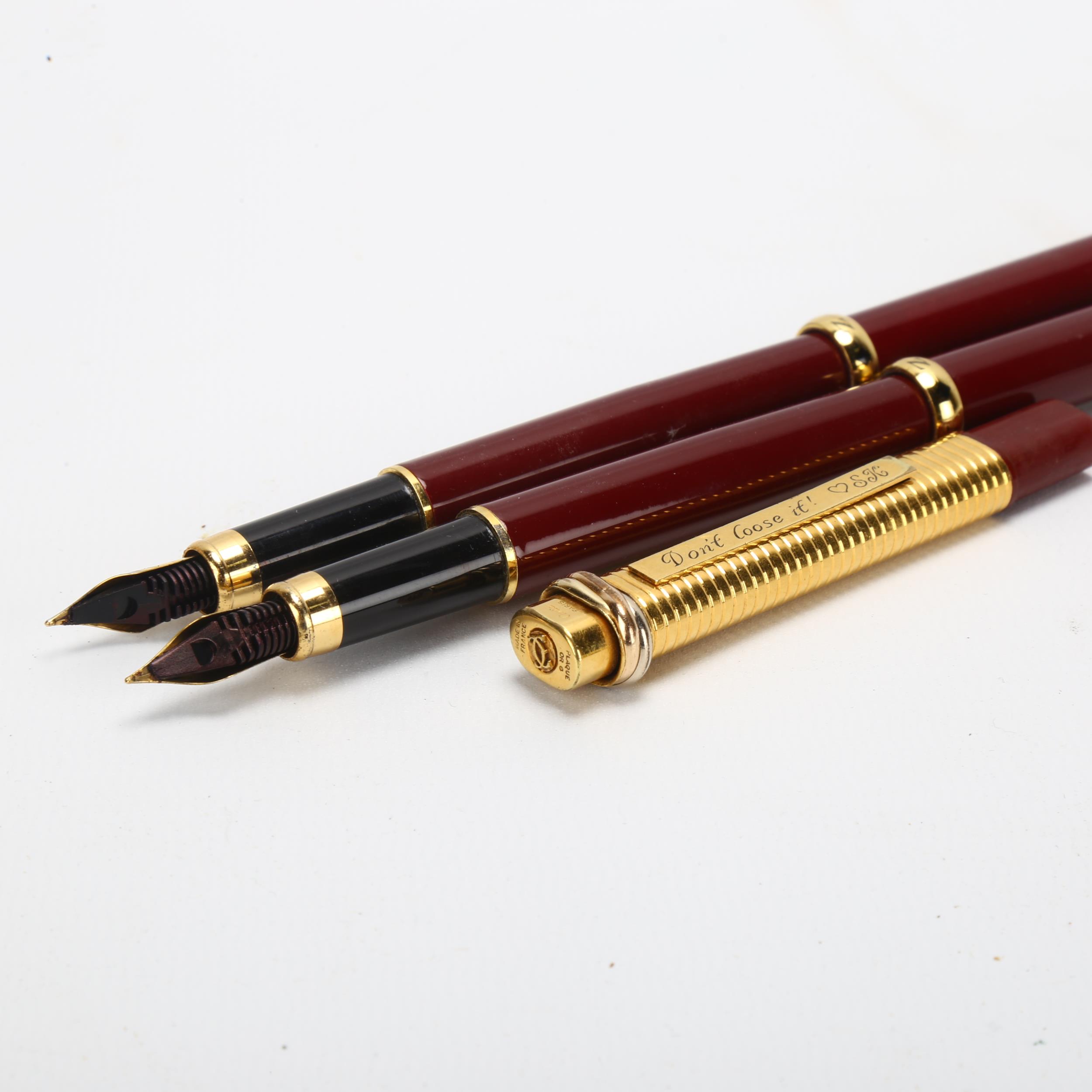 A pair of Morritz burgundy cased fountain pens, and a Cartier gold ...
