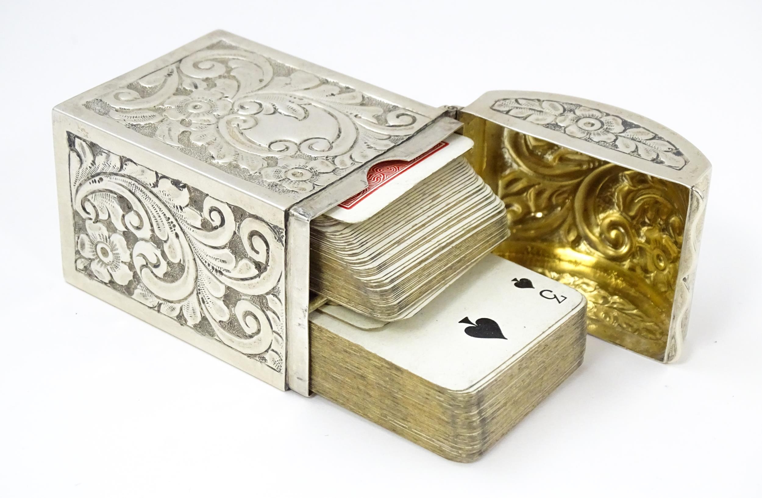 A silver playing card box with embossed floral and foliate decoration ...