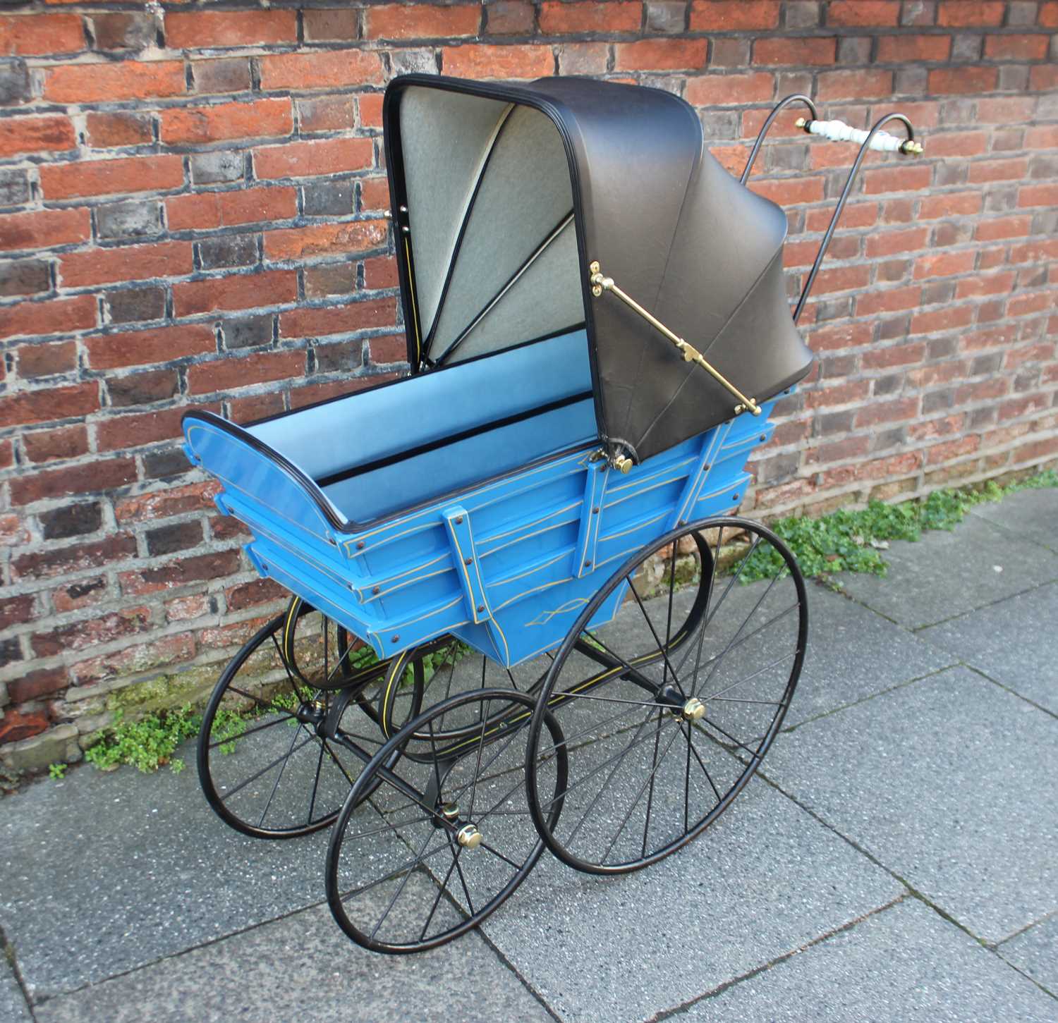 A restored Victorian pram with folding canopy and four spoke wheels ...