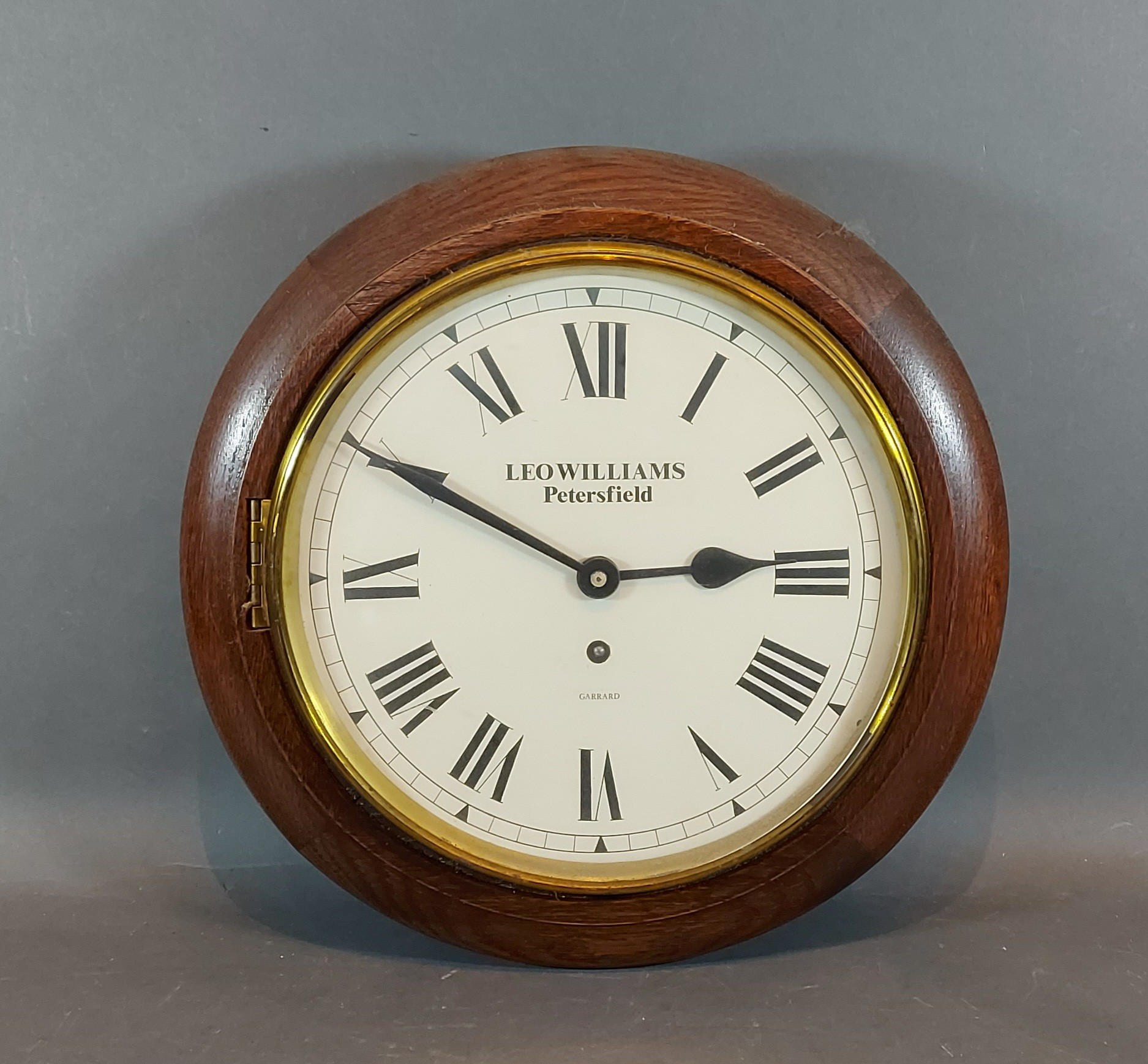 An oak cased circular wall clock by Garrard, retailed by Leo Williams ...