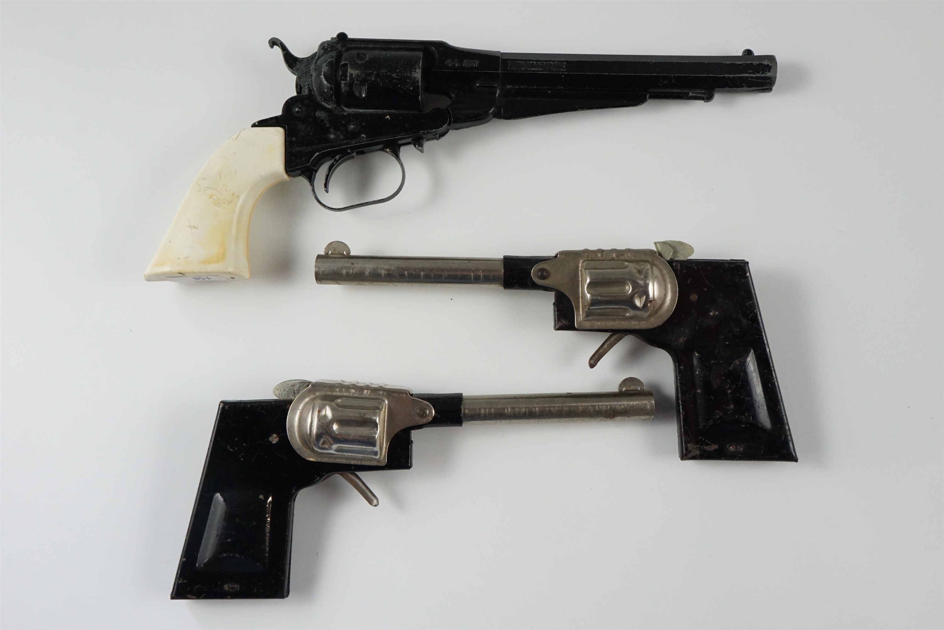 Three vintage toy cap guns including a diecast Remington New Model Army