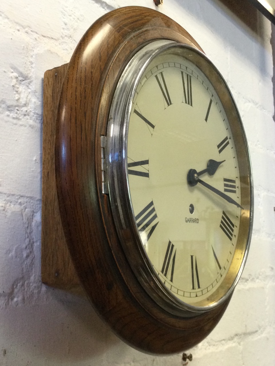 An Edwardian circular oak wall clock by Garrard, the 10in dial with ...