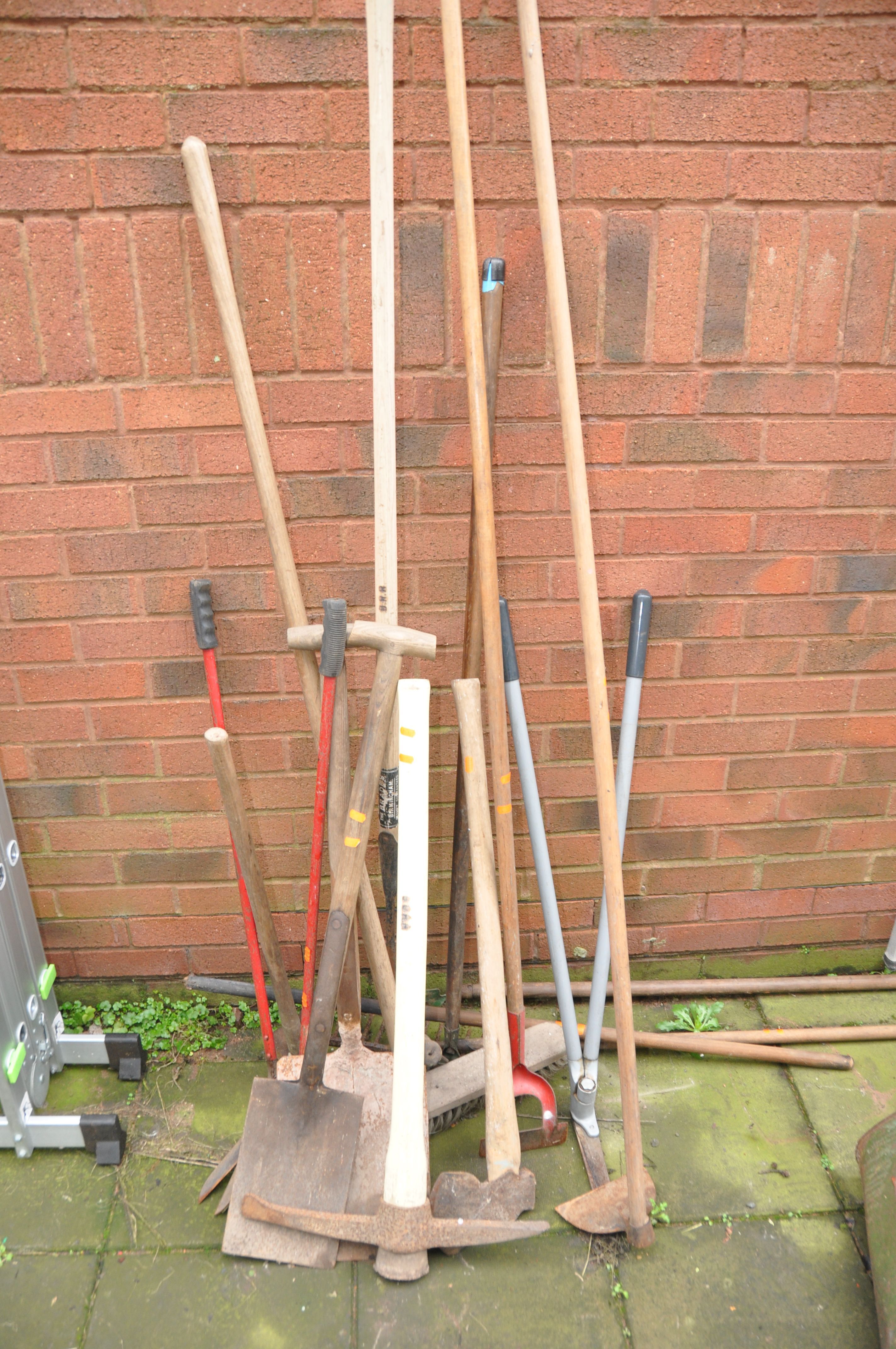 A COLLECTION OF GARDEN TOOLS to include rakes, spade, pick axe, sledge ...