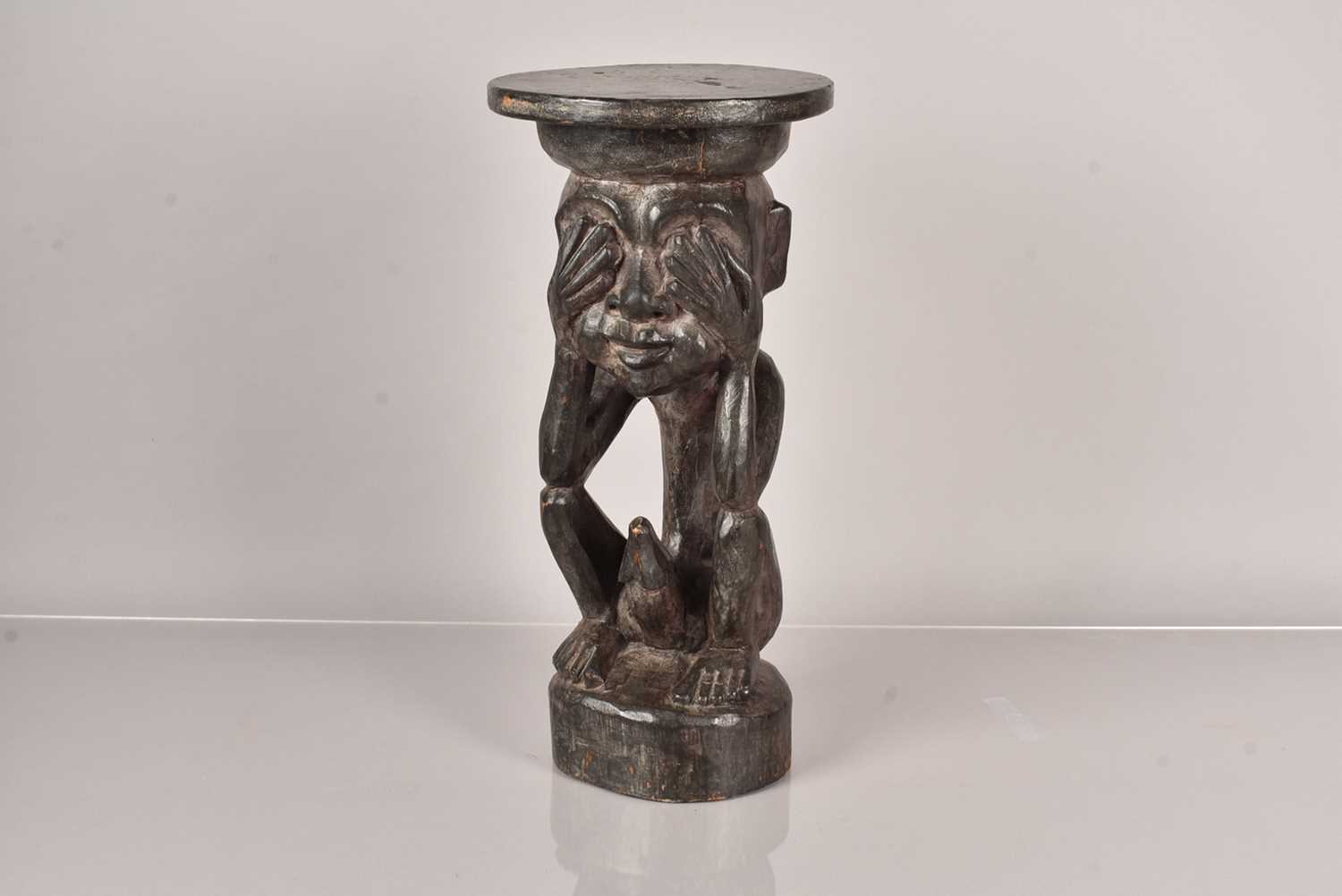 An African carved wooden figural stand, having a carved figure of a ...