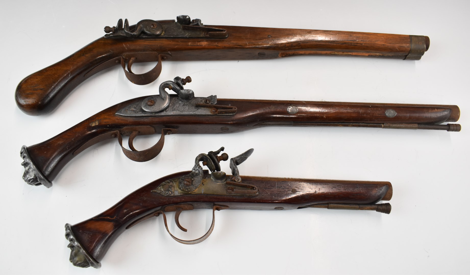 Three decorative flintlock pistols, two with lion mask butt caps ...