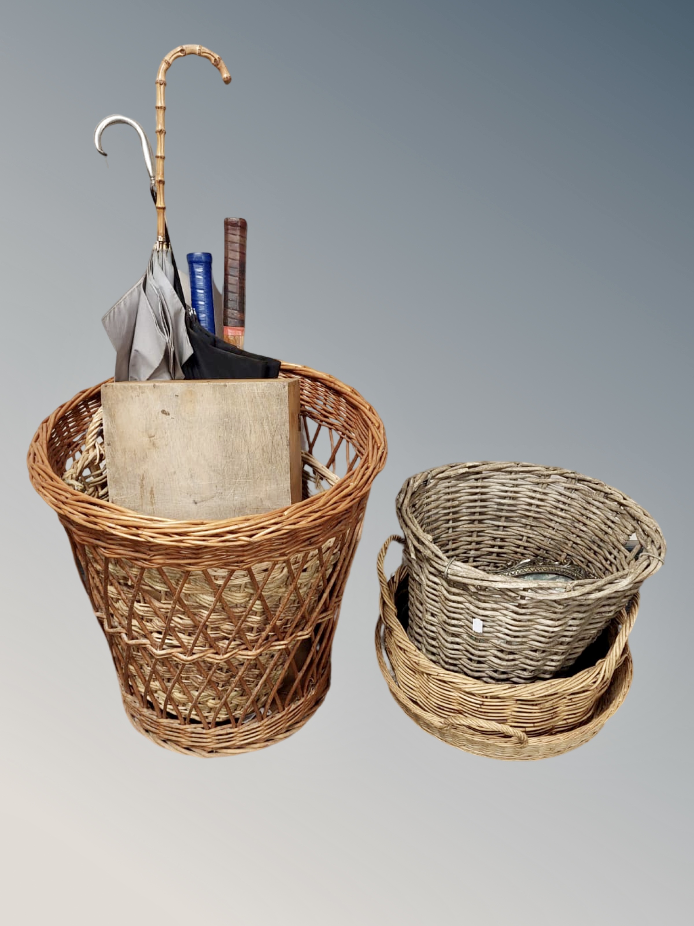 A group of wicker baskets, umbrellas, tennis rackets, framed print ...