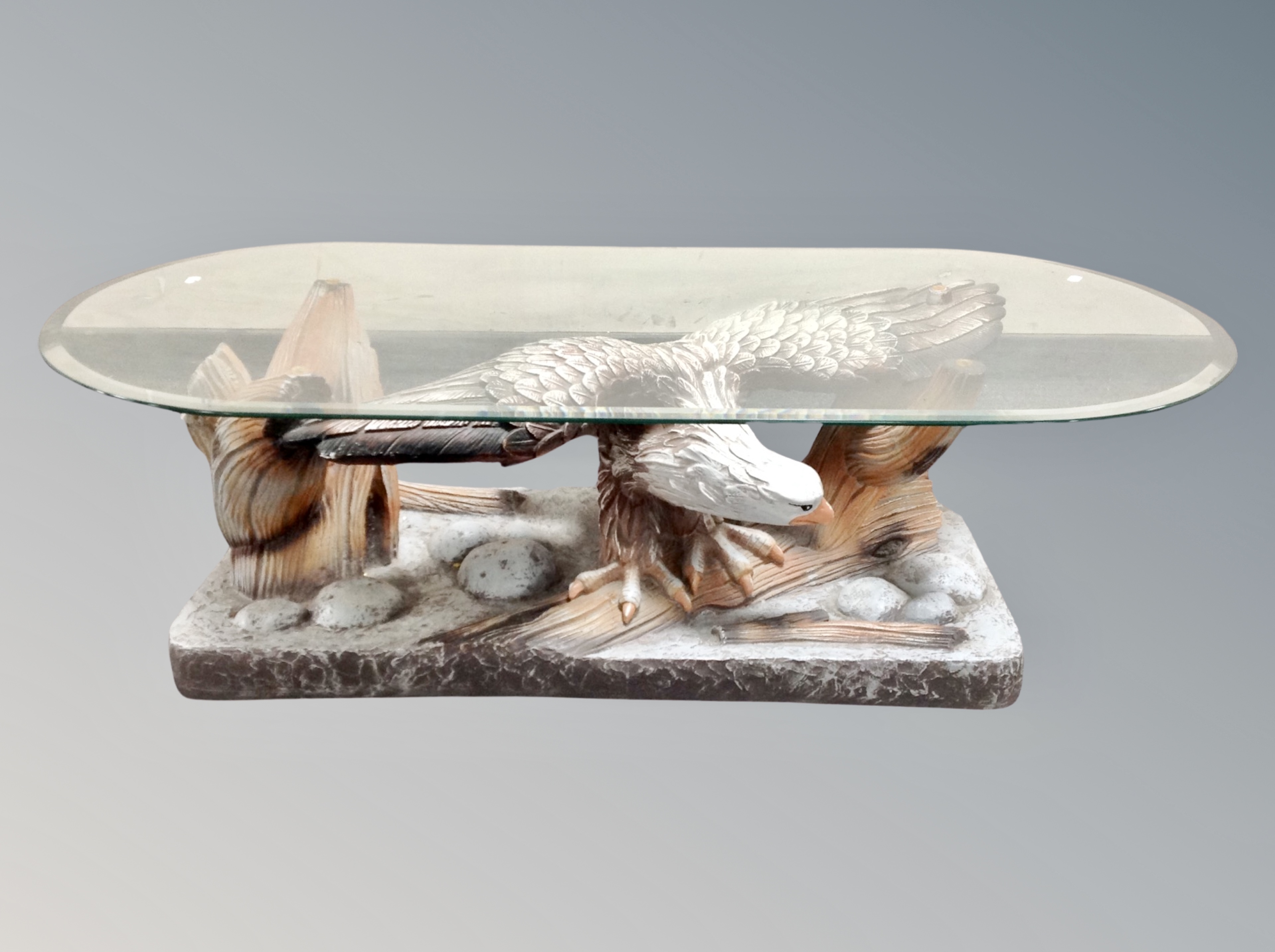 A contemporary glass coffee table on eagle pedestal, length 135 cm