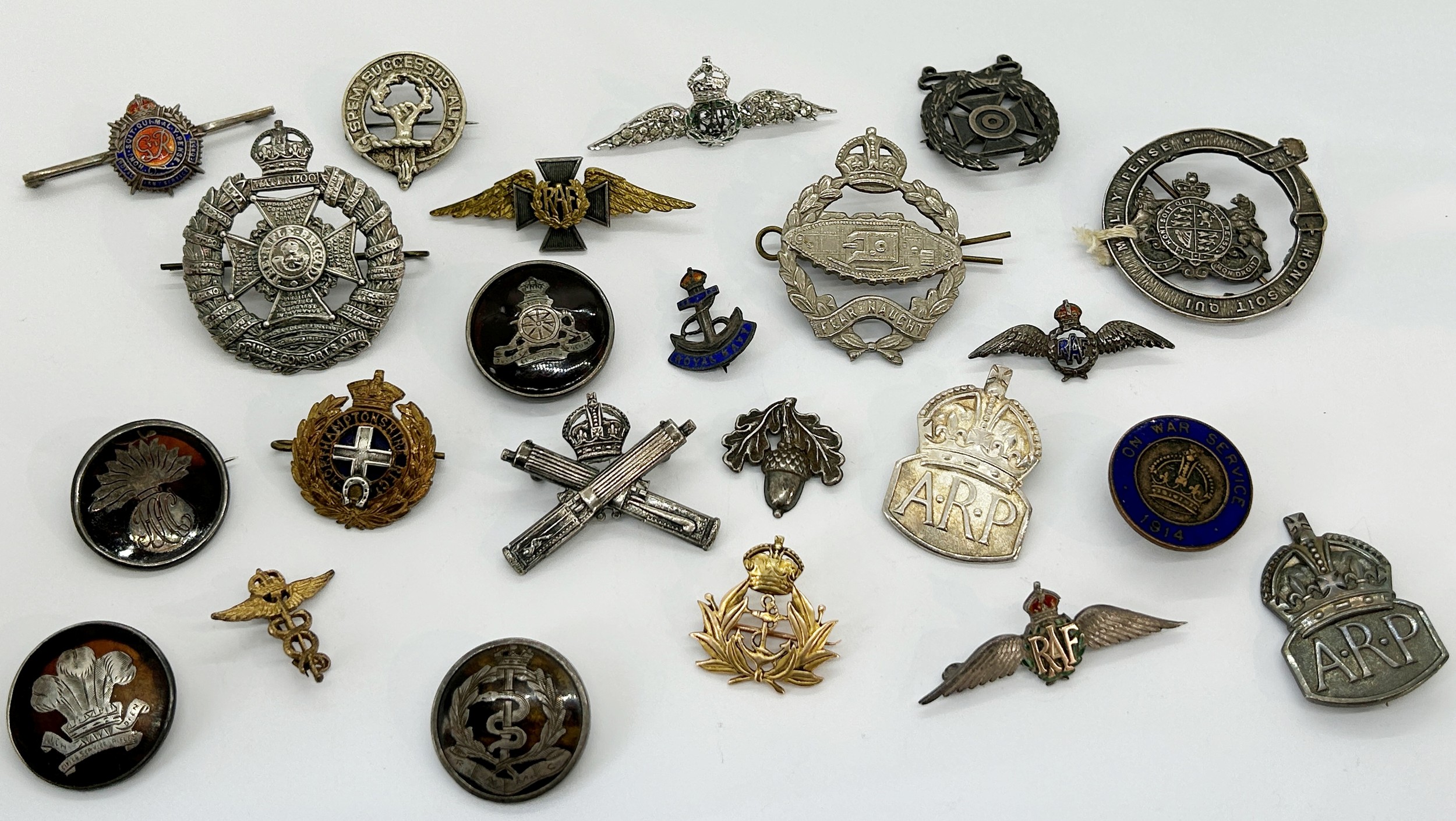 A collection of silver and other military cap badges, lapel badges, etc ...