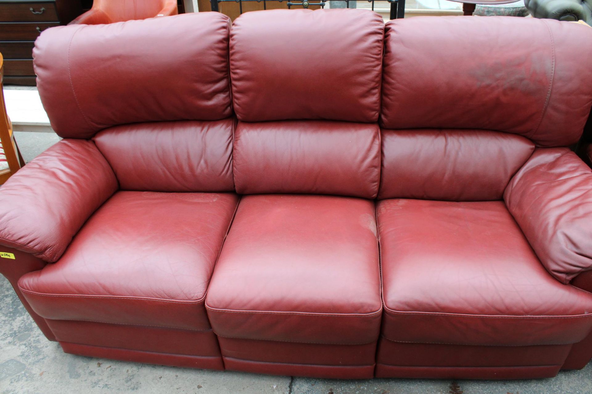A RED LEATHER VIOLINO THREE PIECE SUITE COMPRISING OF A THREE SEATER ...