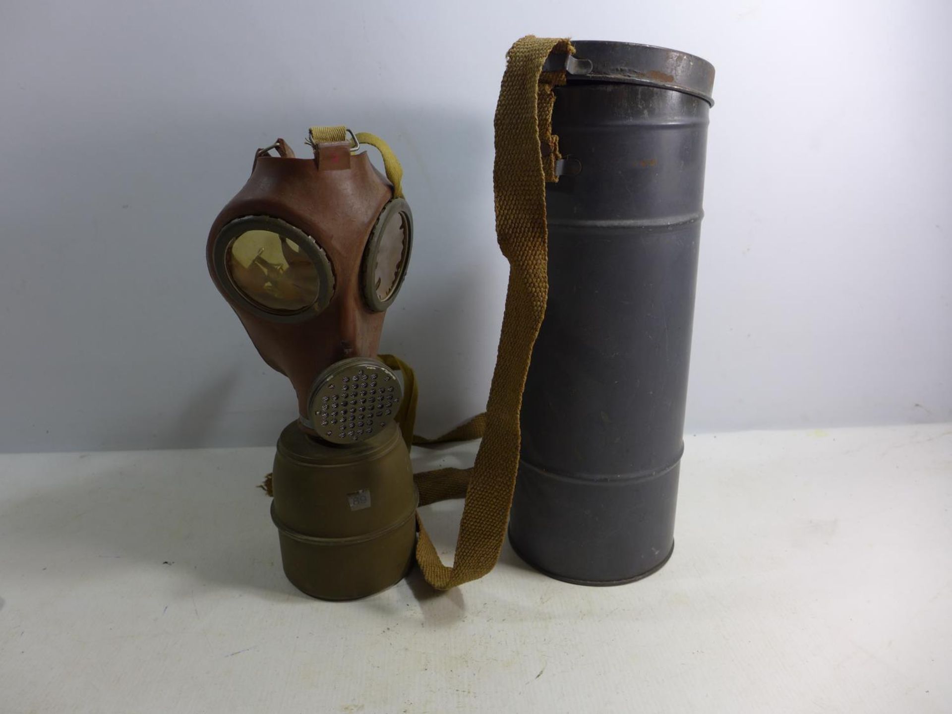 A WORLD WAR II GAS MASK WITH METAL CONTAINER DATED 1939