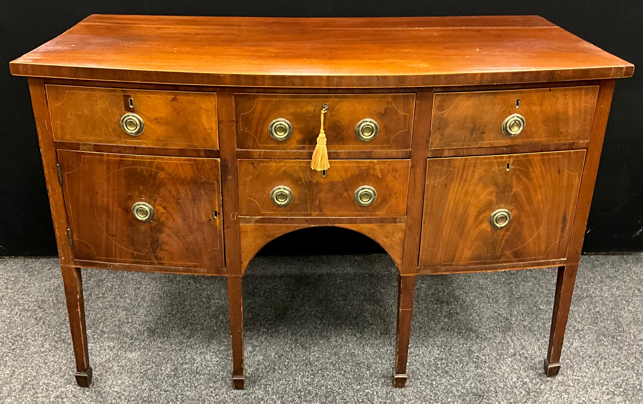 A George III mahogany bow front sideboard, oversailing top above an ...