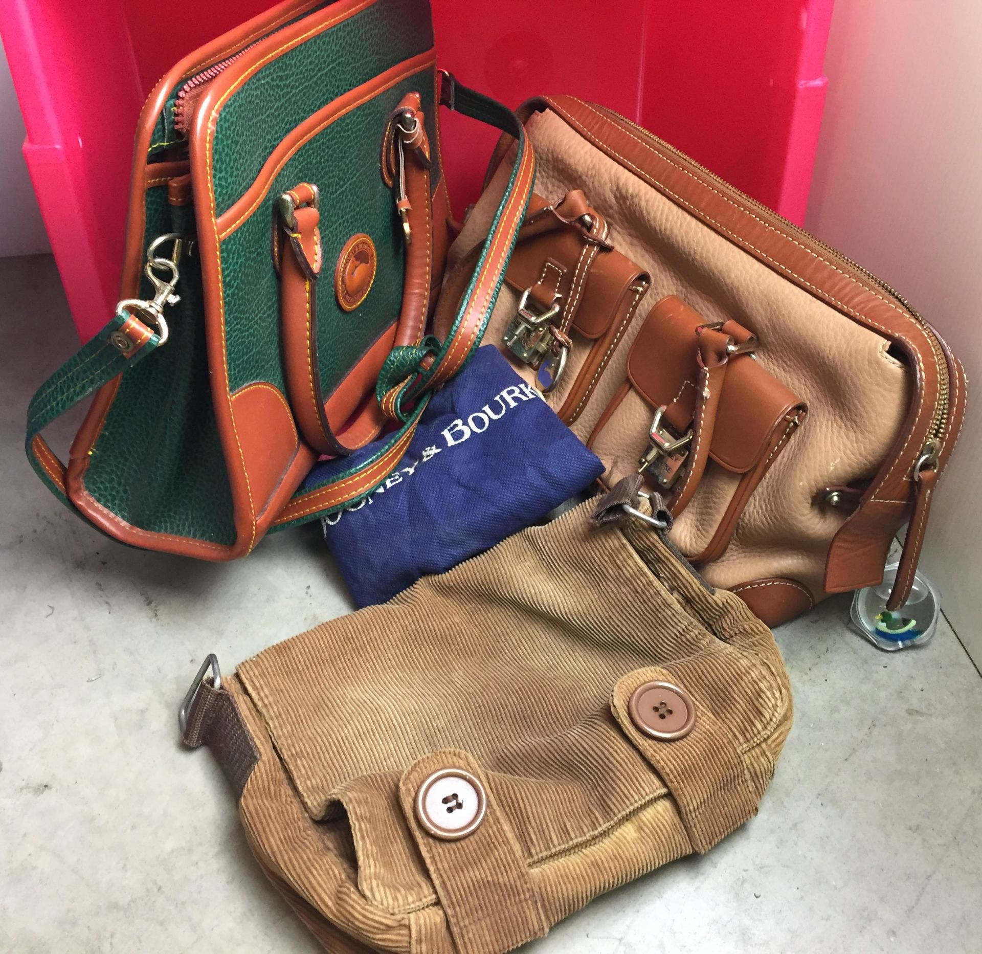 Pink plastic box containing three handbags - two by Dooney & Bourke and ...