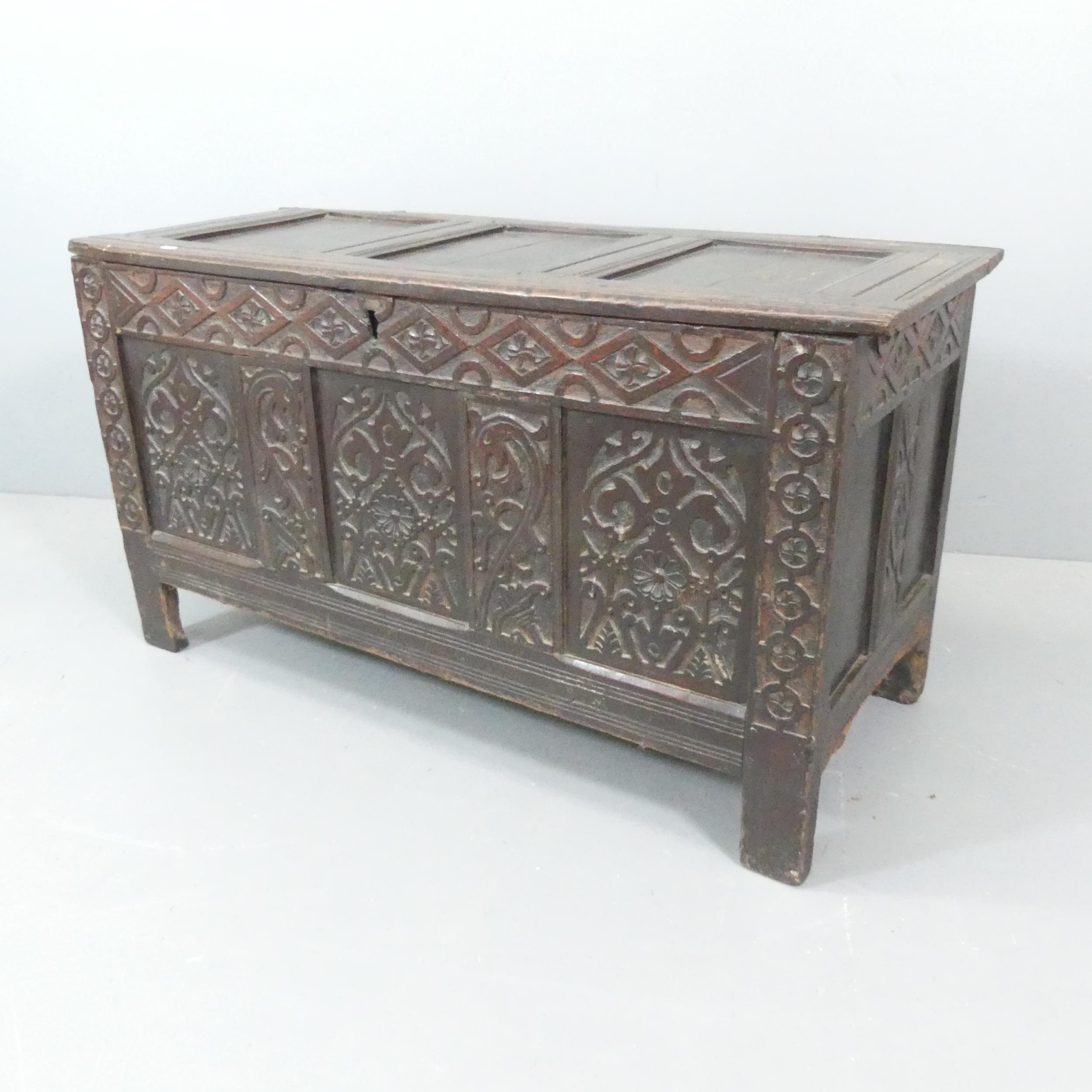 An 18th century panelled oak coffer, with carved decoration and raised ...