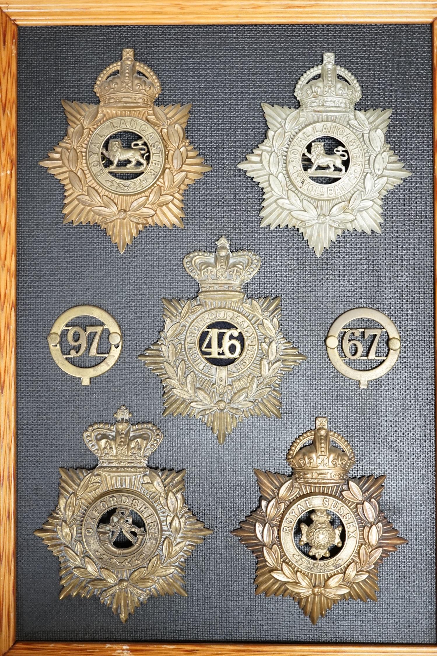 Five military helmet plates and two other centre badges mounted on a ...