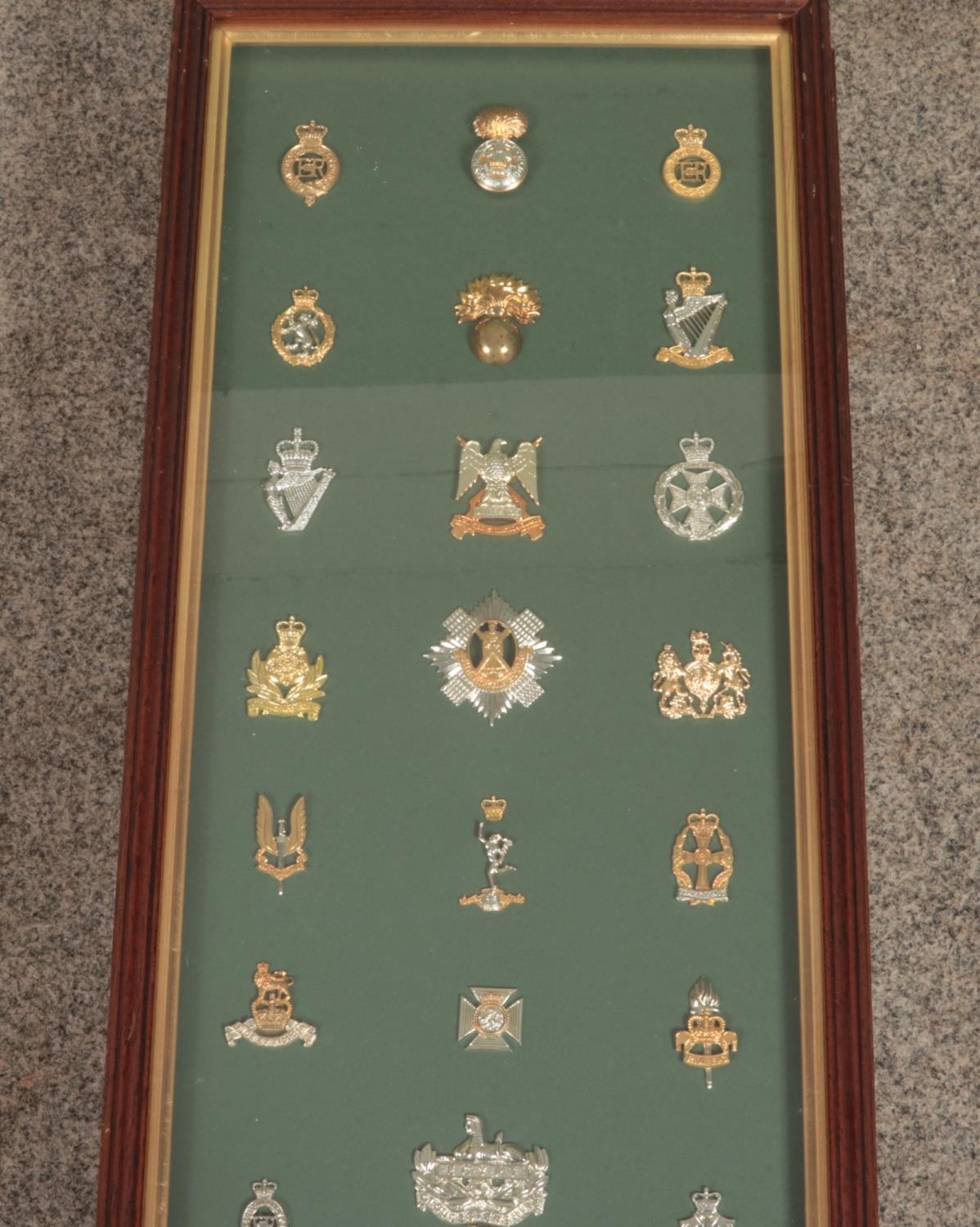 A large framed display of 31 military cap badges. Includes Grenadier ...