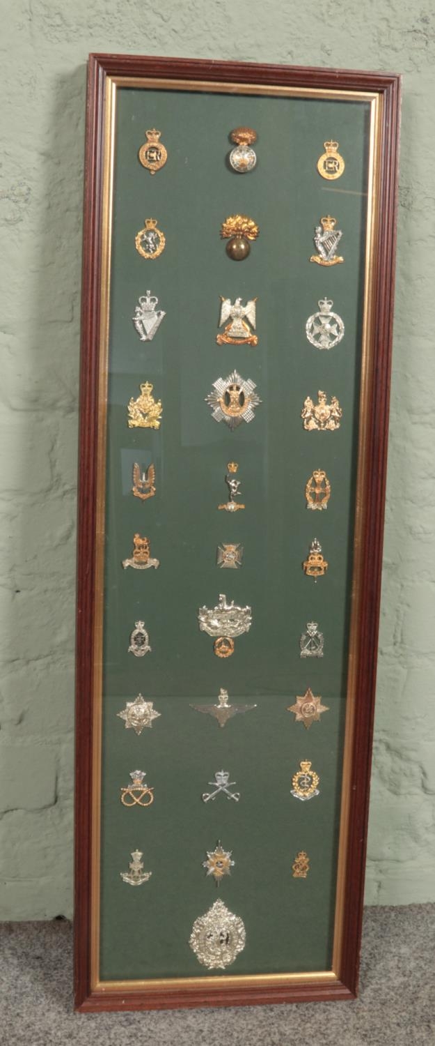 A large framed display of 31 military cap badges. Includes Grenadier ...