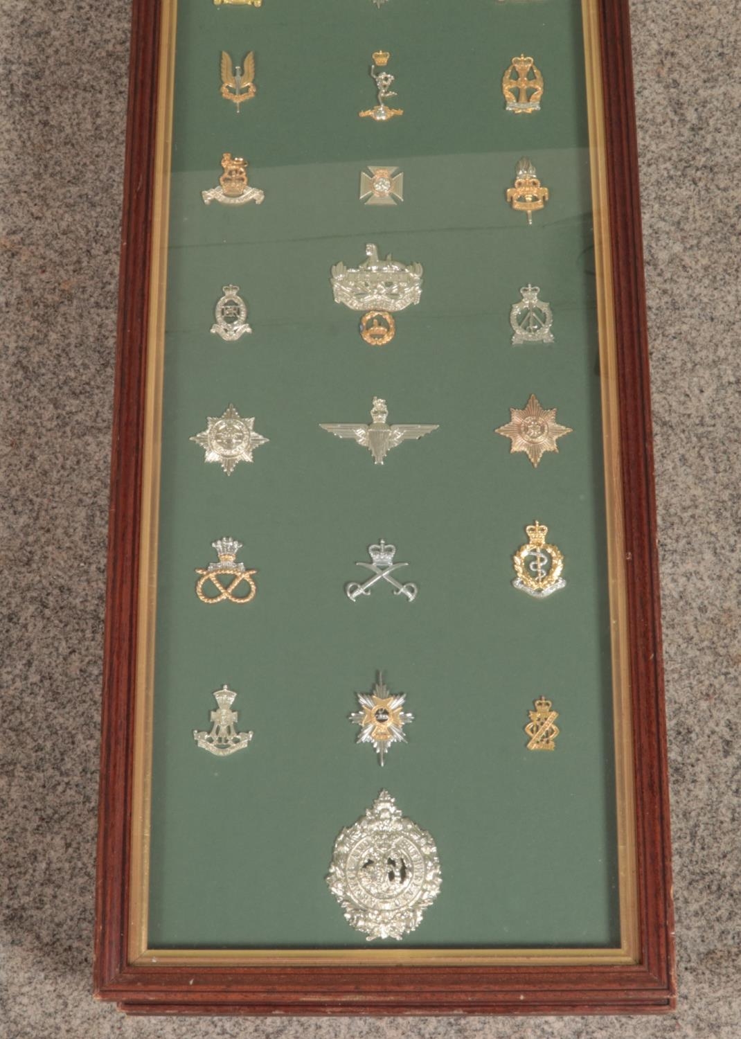 A large framed display of 31 military cap badges. Includes Grenadier ...