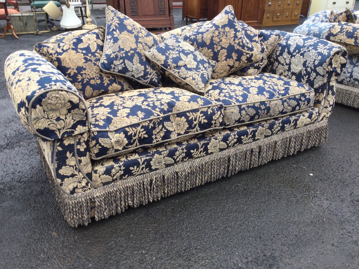 A Peter Guild camelback sofa with padded arms and loose cushions above ...