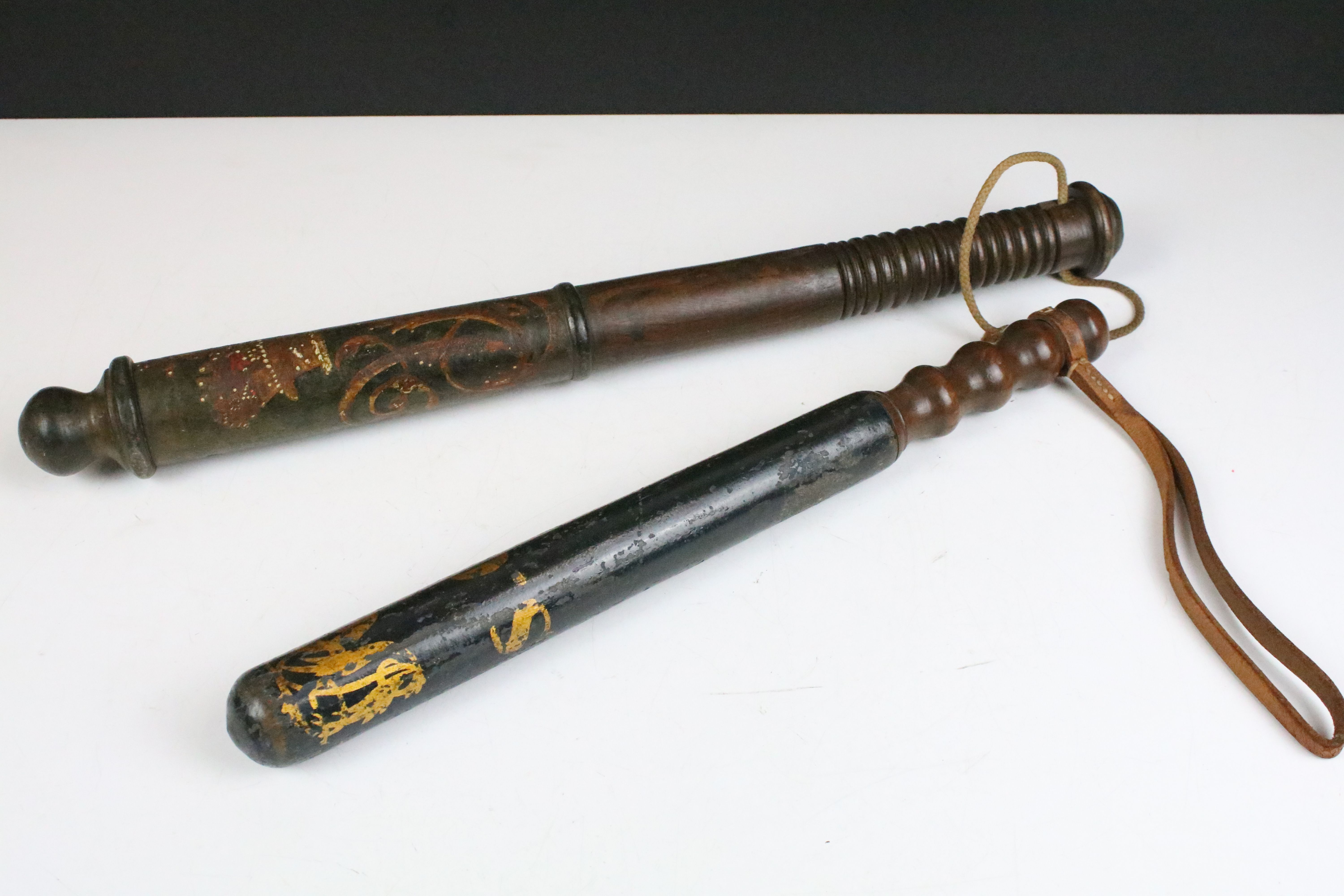 Two truncheons, the smaller with painted insignia, indistinct, possibly ...