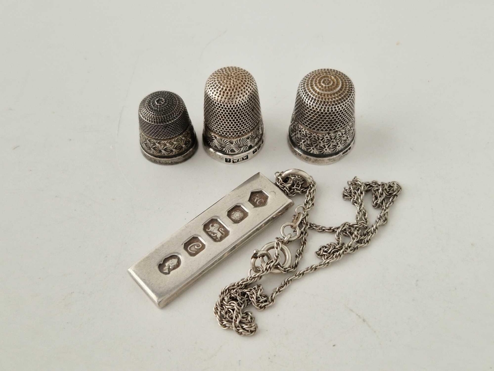A silver ingot on chain and three thimbles