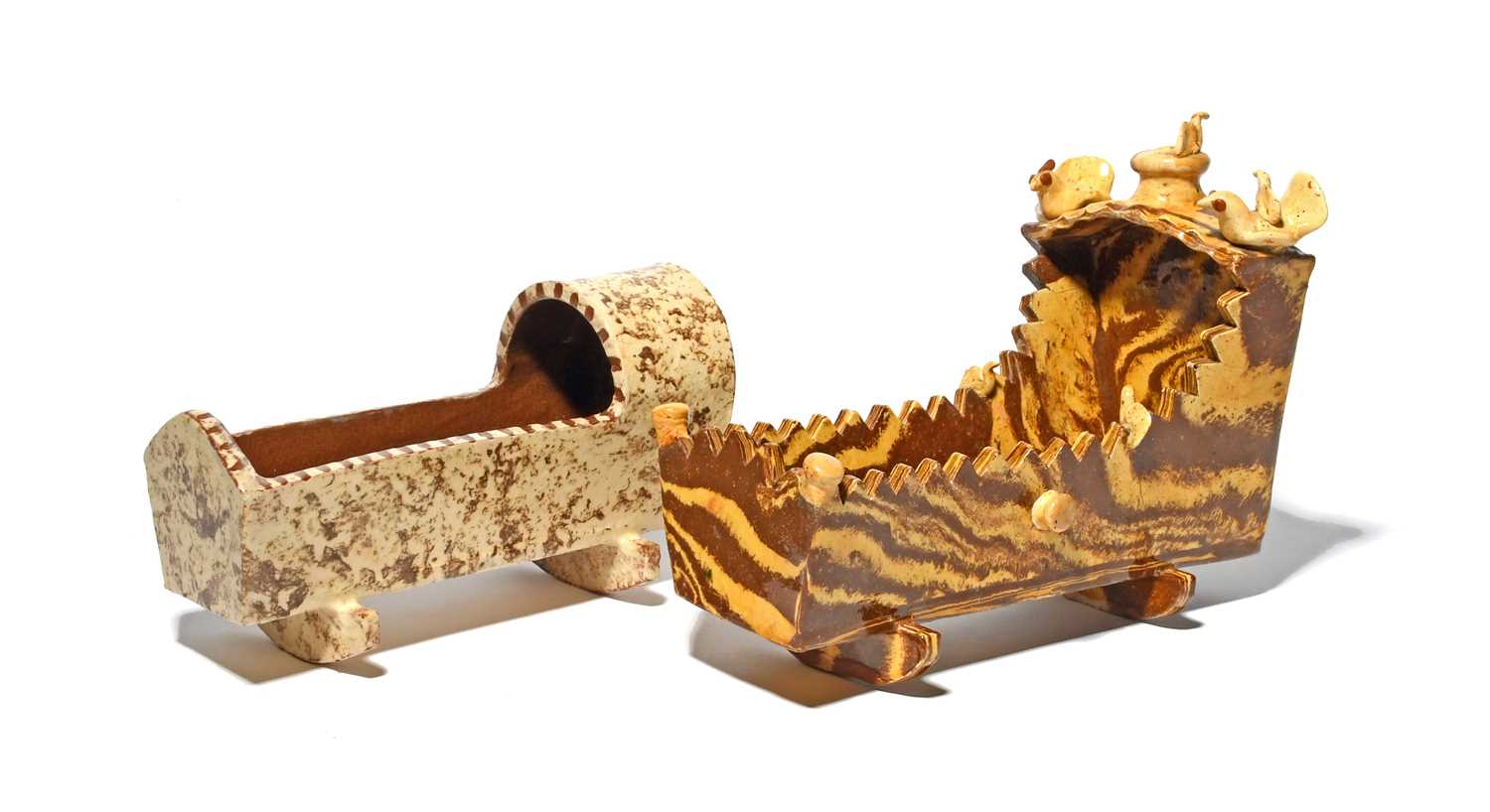 Two slipware models of cradles, 19th century, one with cream and brown ...