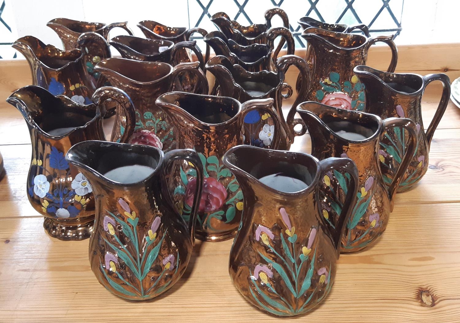 A mixed collection of 16 antique copper lustre jugs, each painted with ...