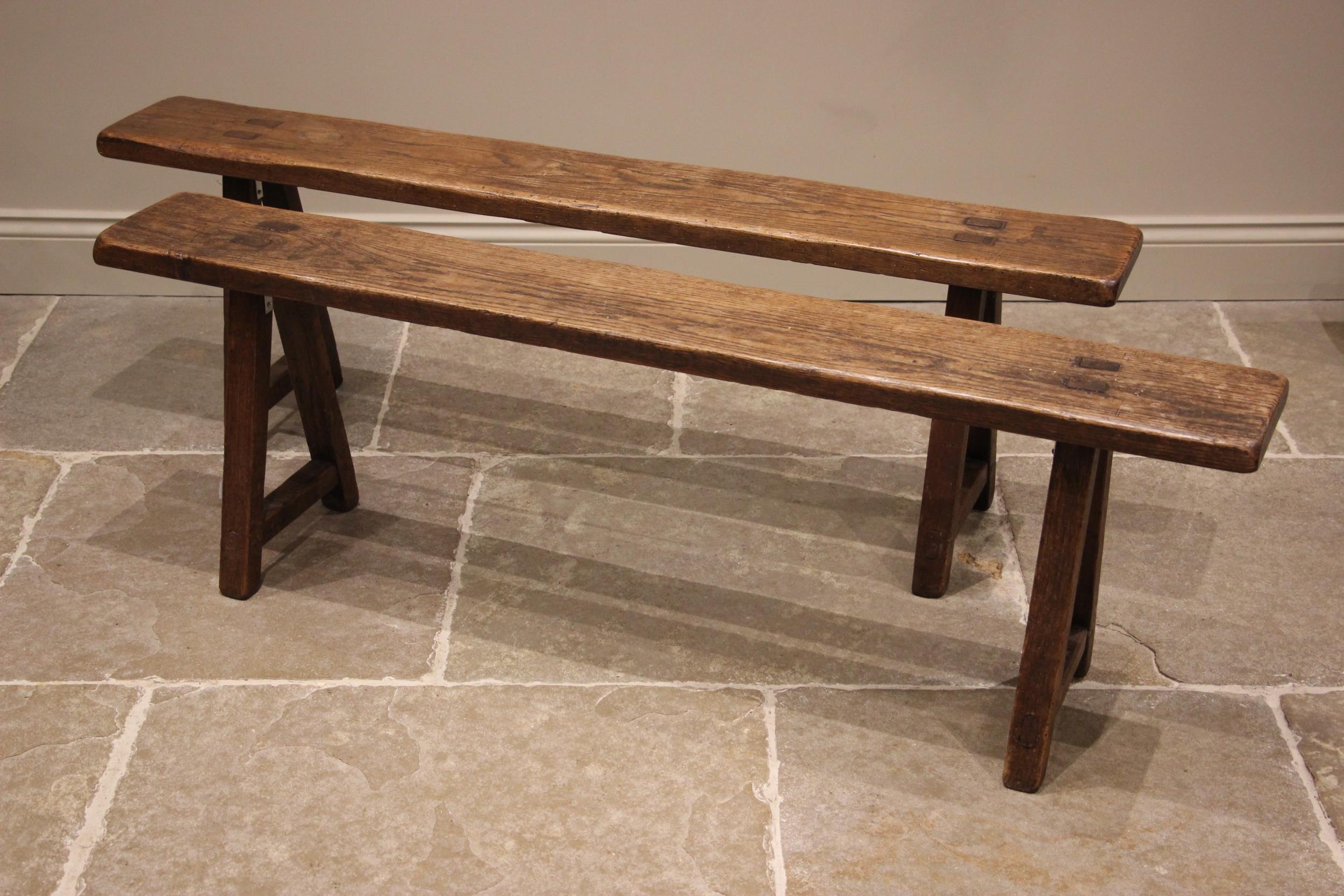A pair of oak benches or forms, 19th century, each with a plank top ...